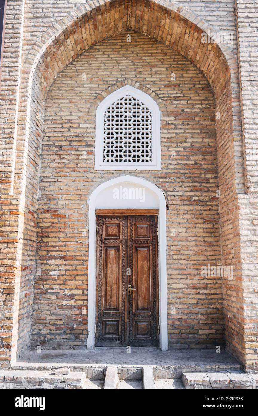 ancient carved wooden door with oriental Uzbek pattern in brick wall ...