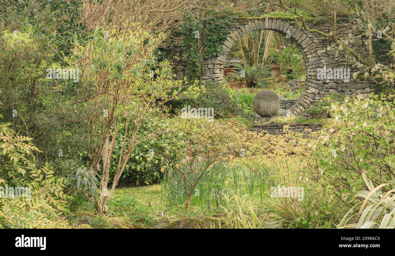 Moon door and concrete ball shape in an overgrown garden as spring ...