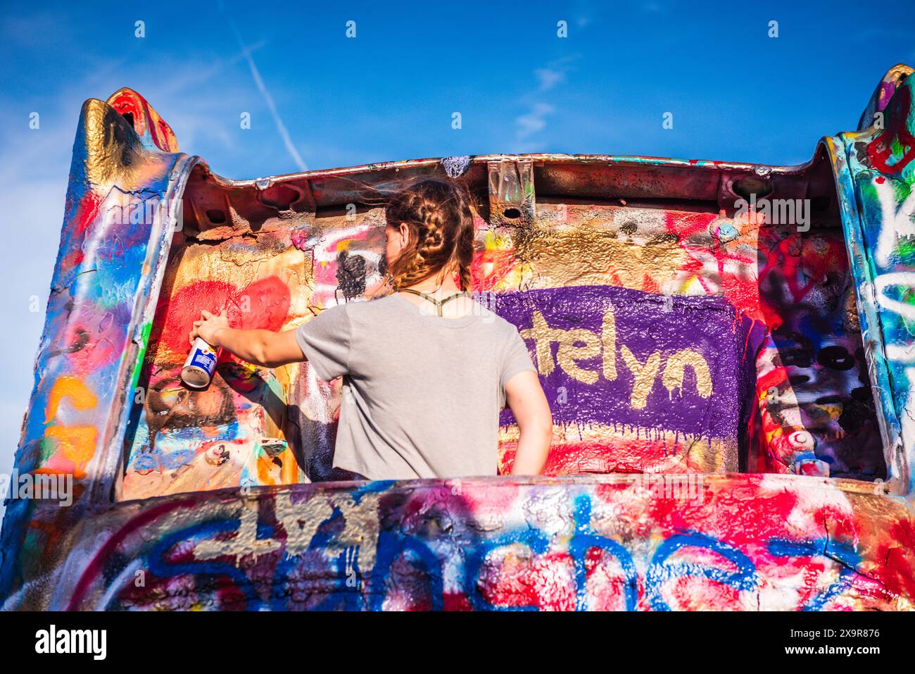 Girl spray painting car at Cadillac Ranch, the public art installation ...