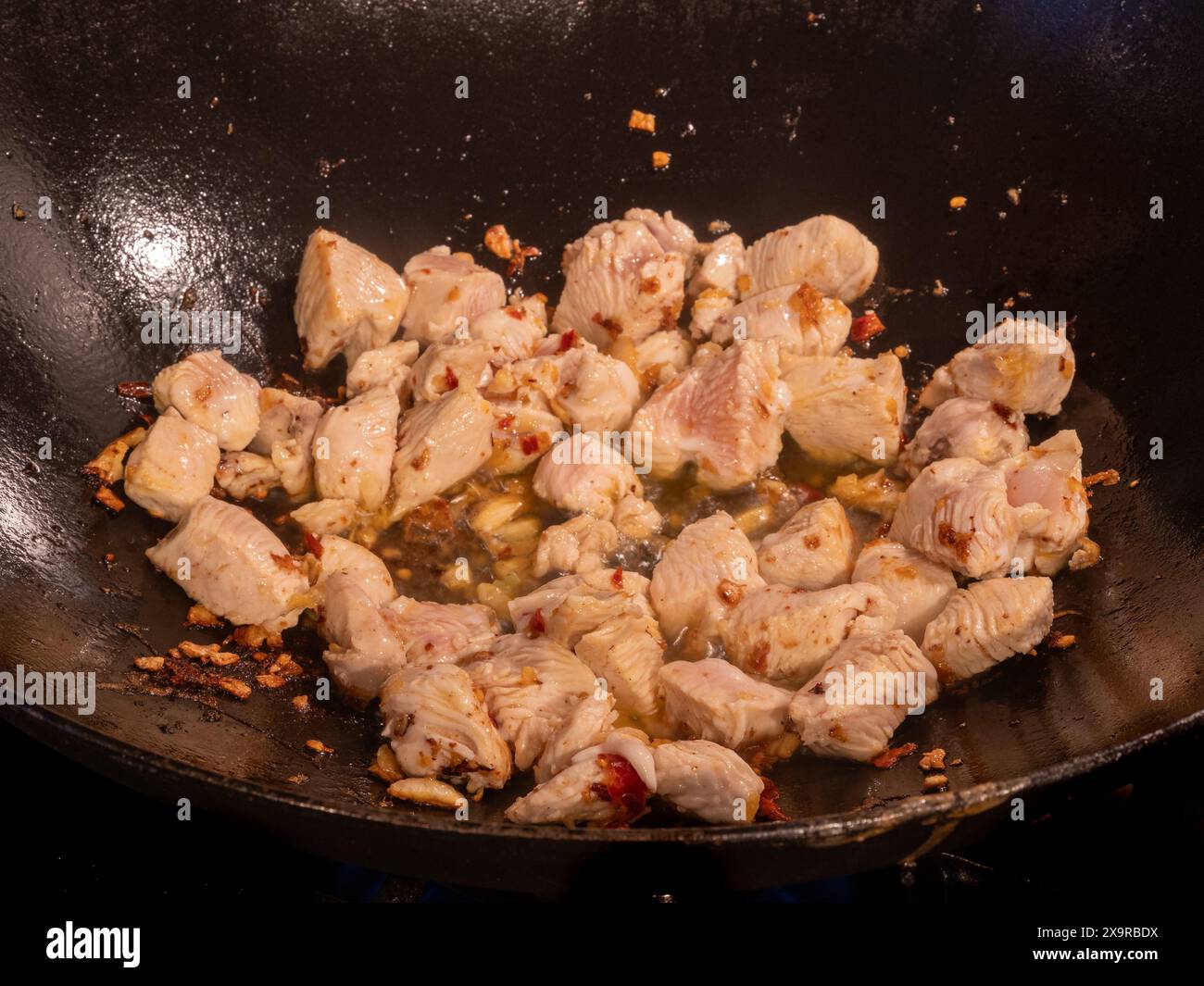 Tender chicken sizzles in a cast iron wok alongside fiery red chilies ...