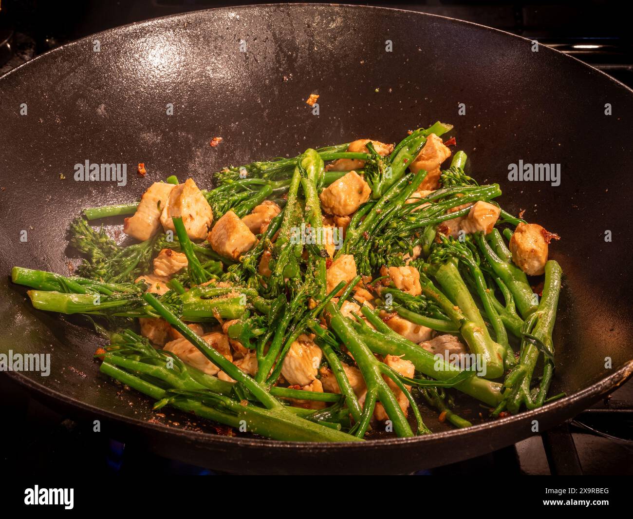 A cast iron wok bursts with flavor as chicken, broccolini, fiery ...