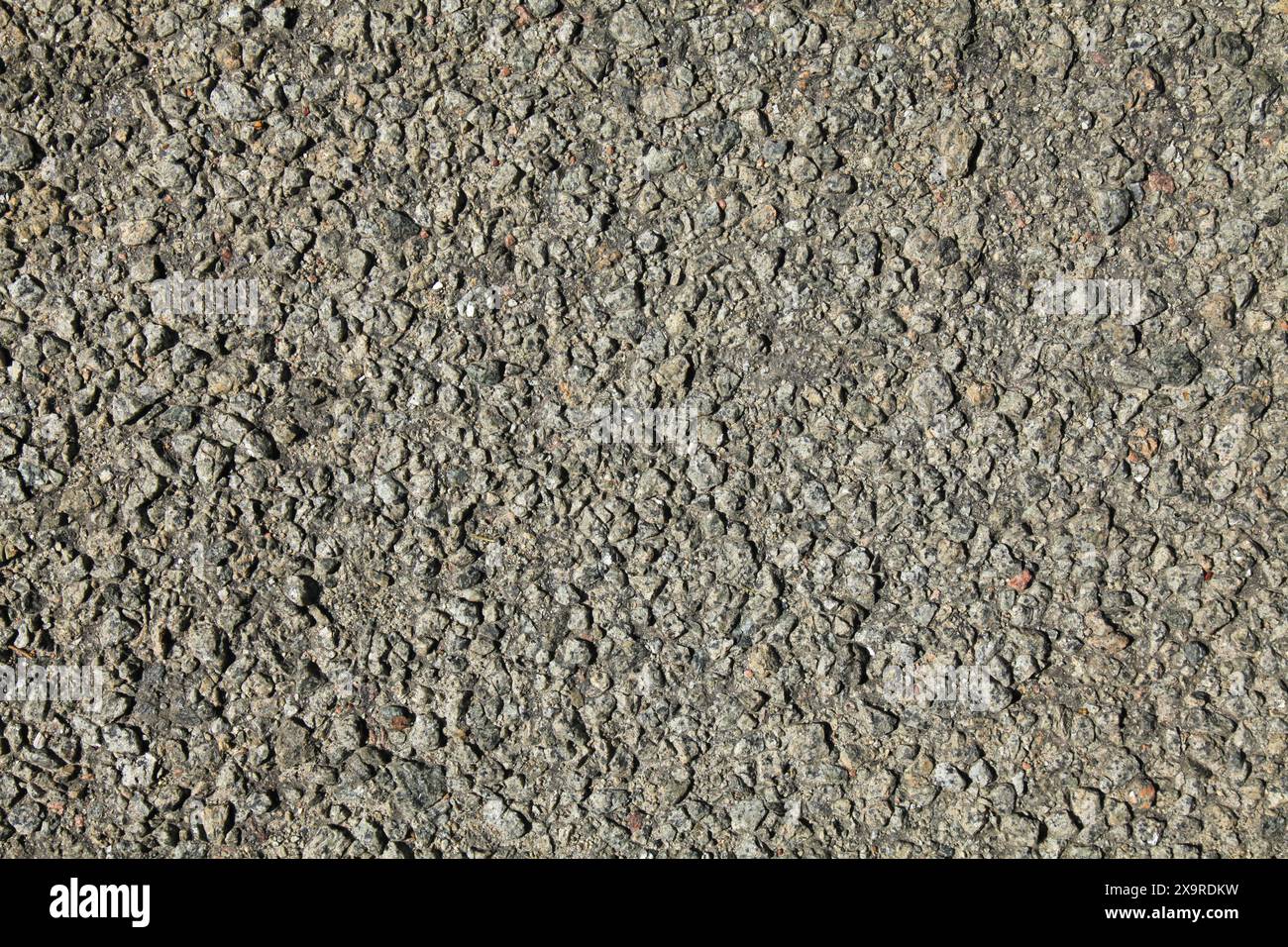 Grey road backdrop. Asphalt surface, covered with stones on the resin ...