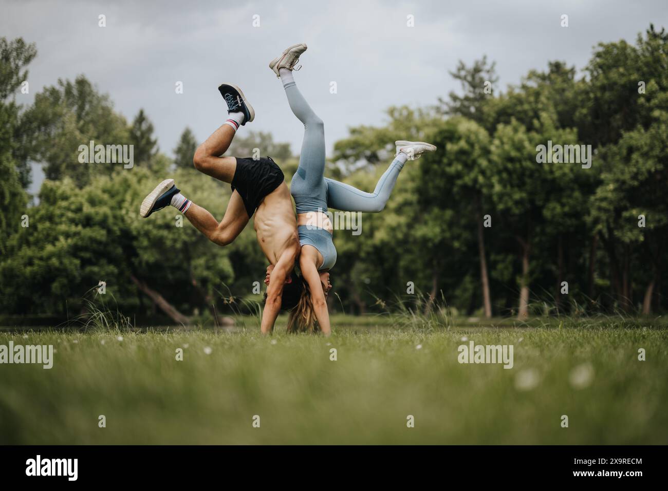 Two people practicing handstands outdoors in a park setting Stock Photo ...