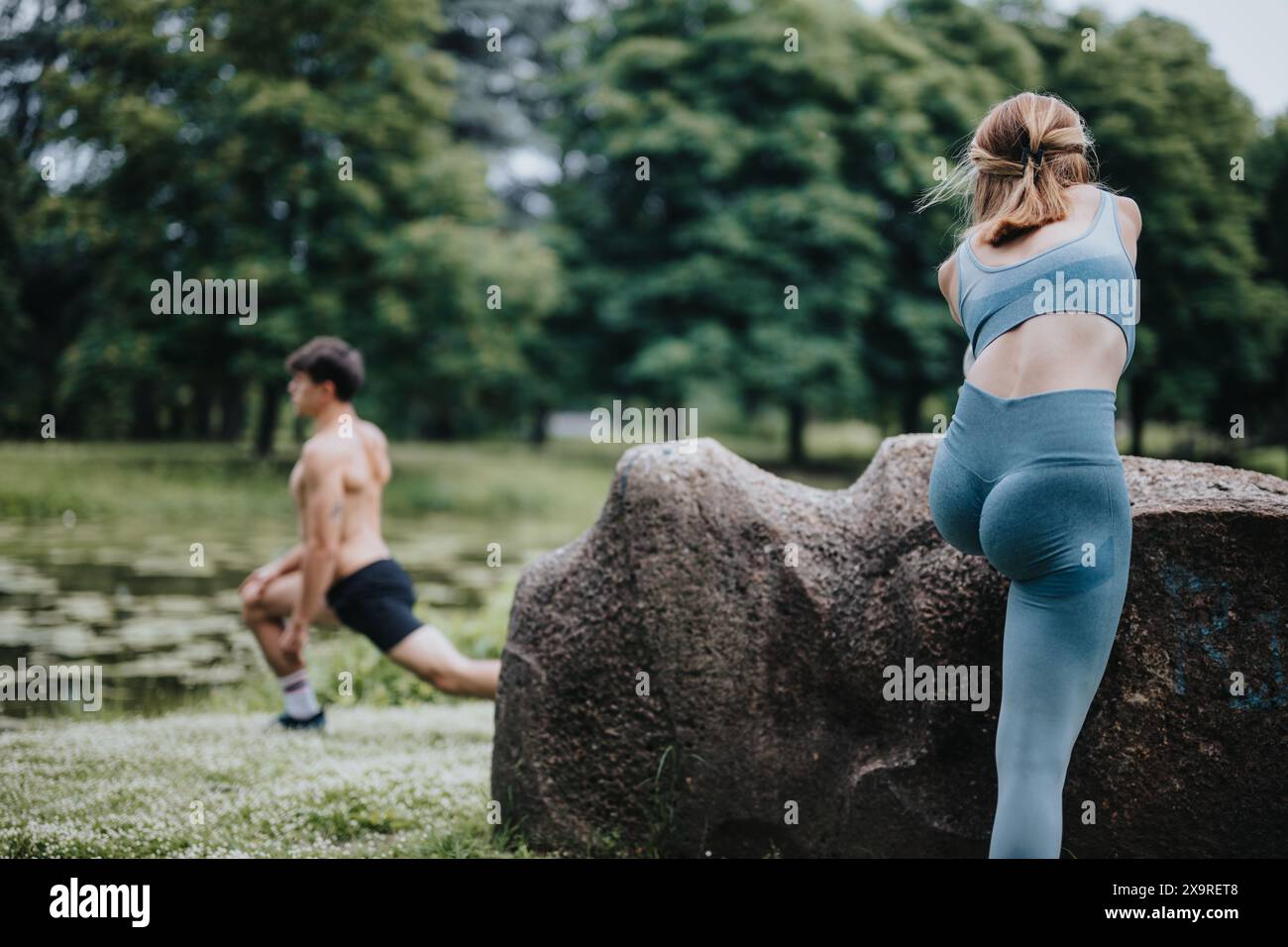 Two people performing outdoor calisthenics exercises near a rock in a ...