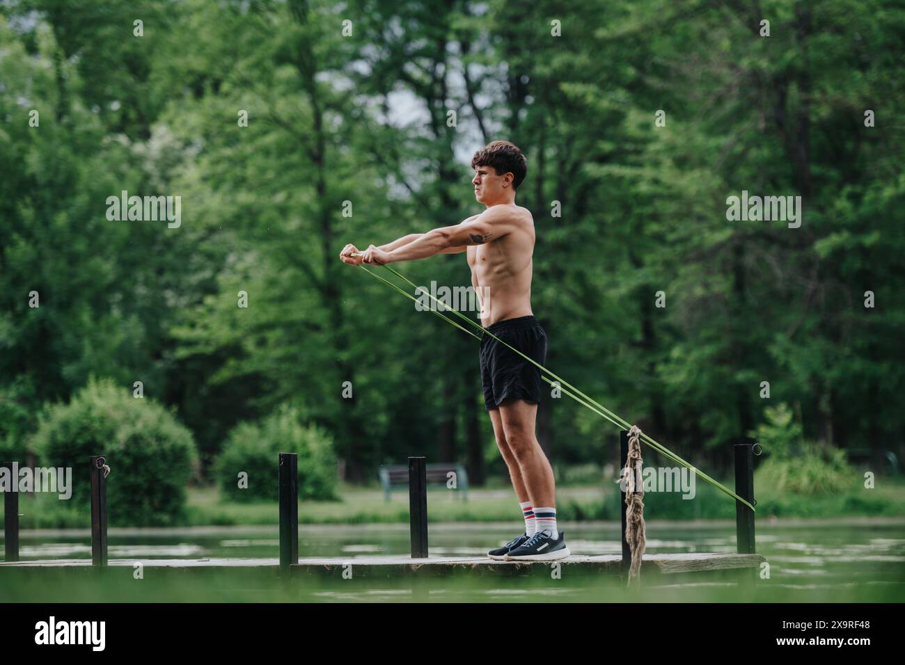Man exercising arms and back muscles with resistance band outside in ...