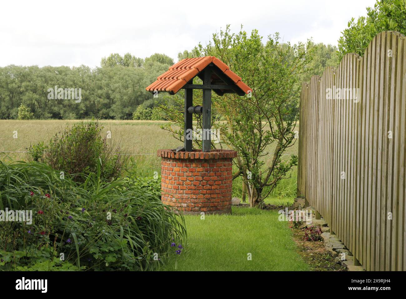 a historic borehole in a garden and a green grassland in the background ...