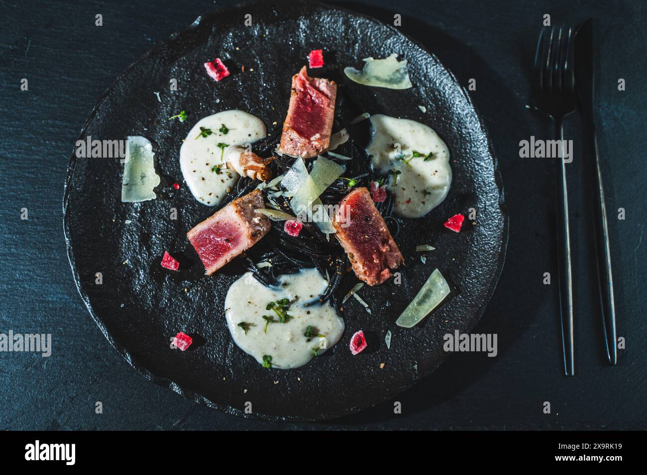 Cooked juicy tuna steak with vegetables and cuttlefish ink spaghetti on ...
