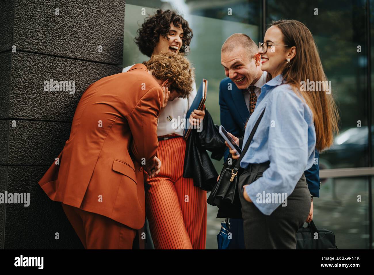Group of young business professionals laughing outdoors during a casual ...