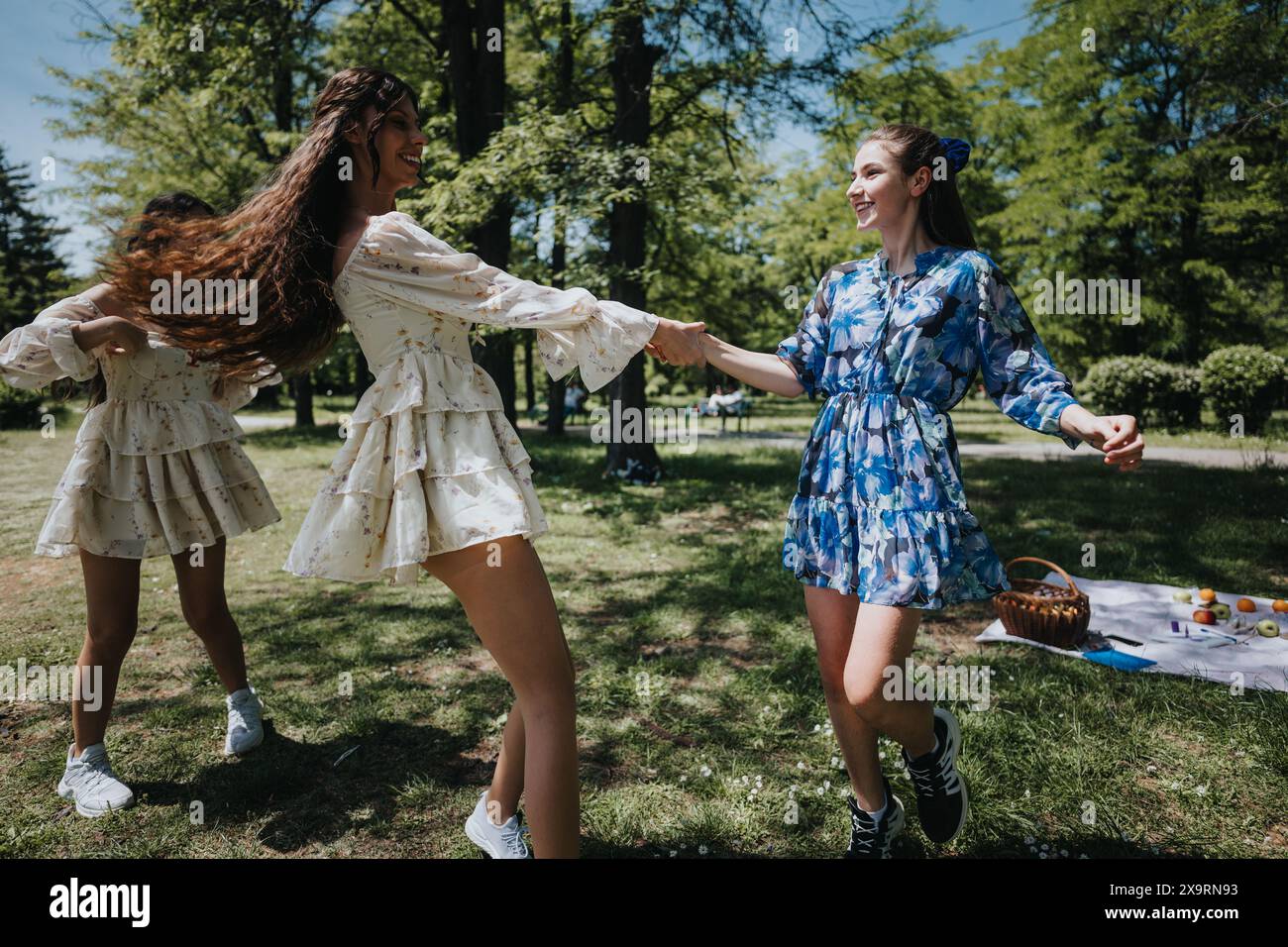 Joyful young women dancing in a sunny park during springtime, embodying ...