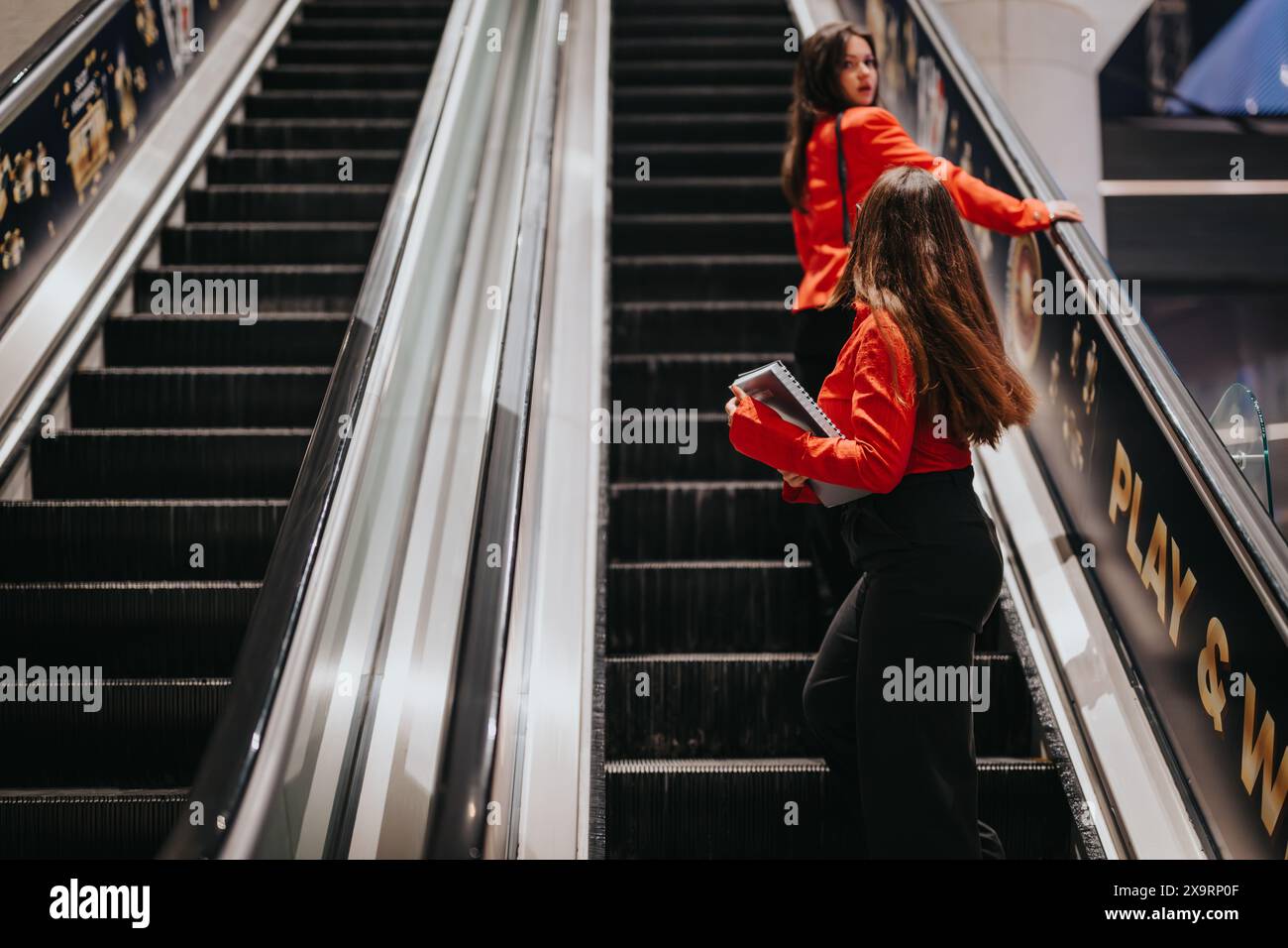 Young corporate business partners riding escalator in office building ...