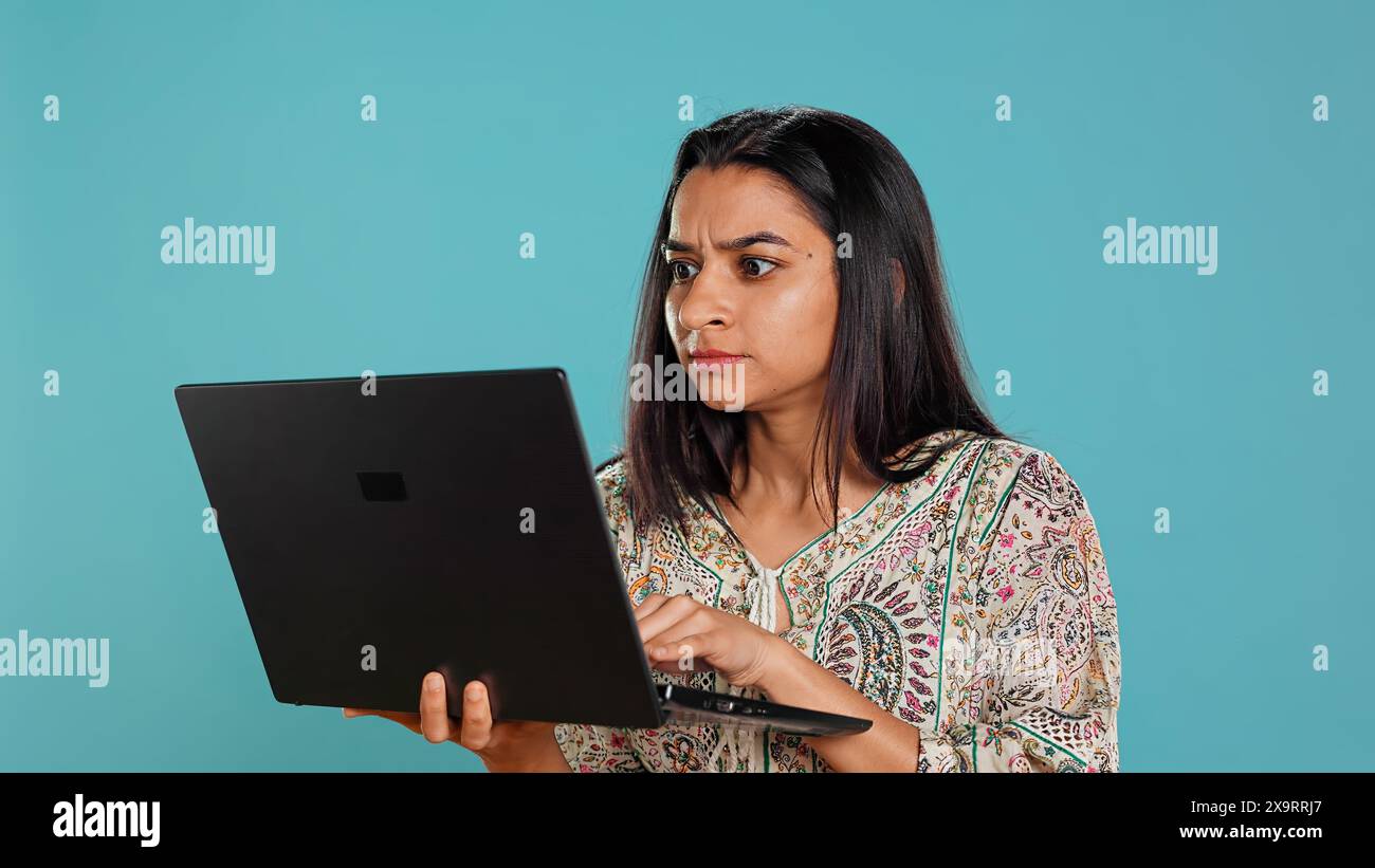 Indian woman typing on laptop keyboard and cursing, feeling angry at ...