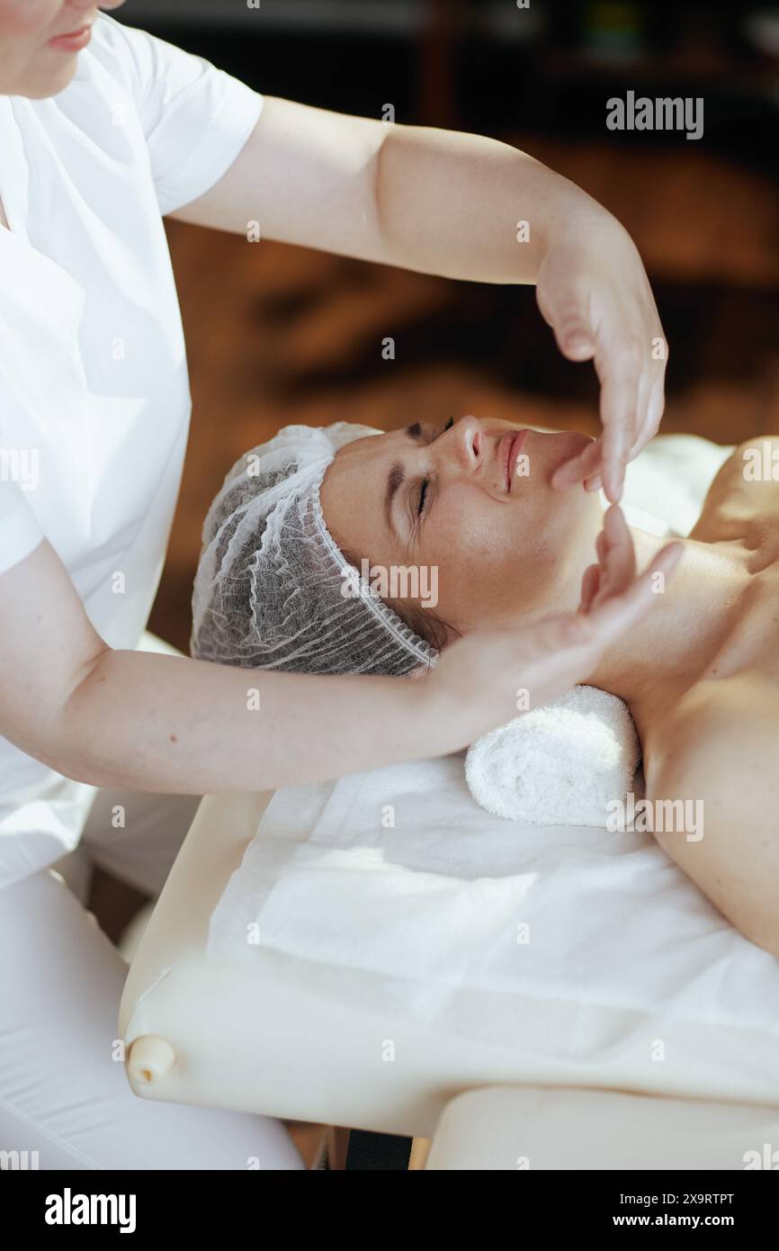Healthcare time. massage therapist in spa salon massaging clients face on massage table Stock ...
