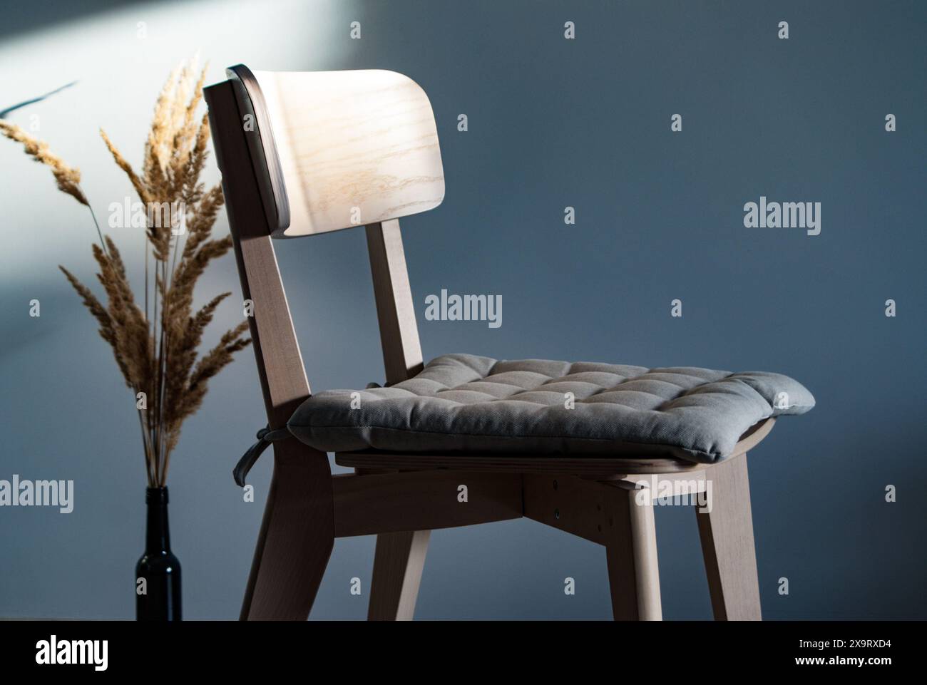 A simple light wooden chair with a pillow in the rays of the setting ...