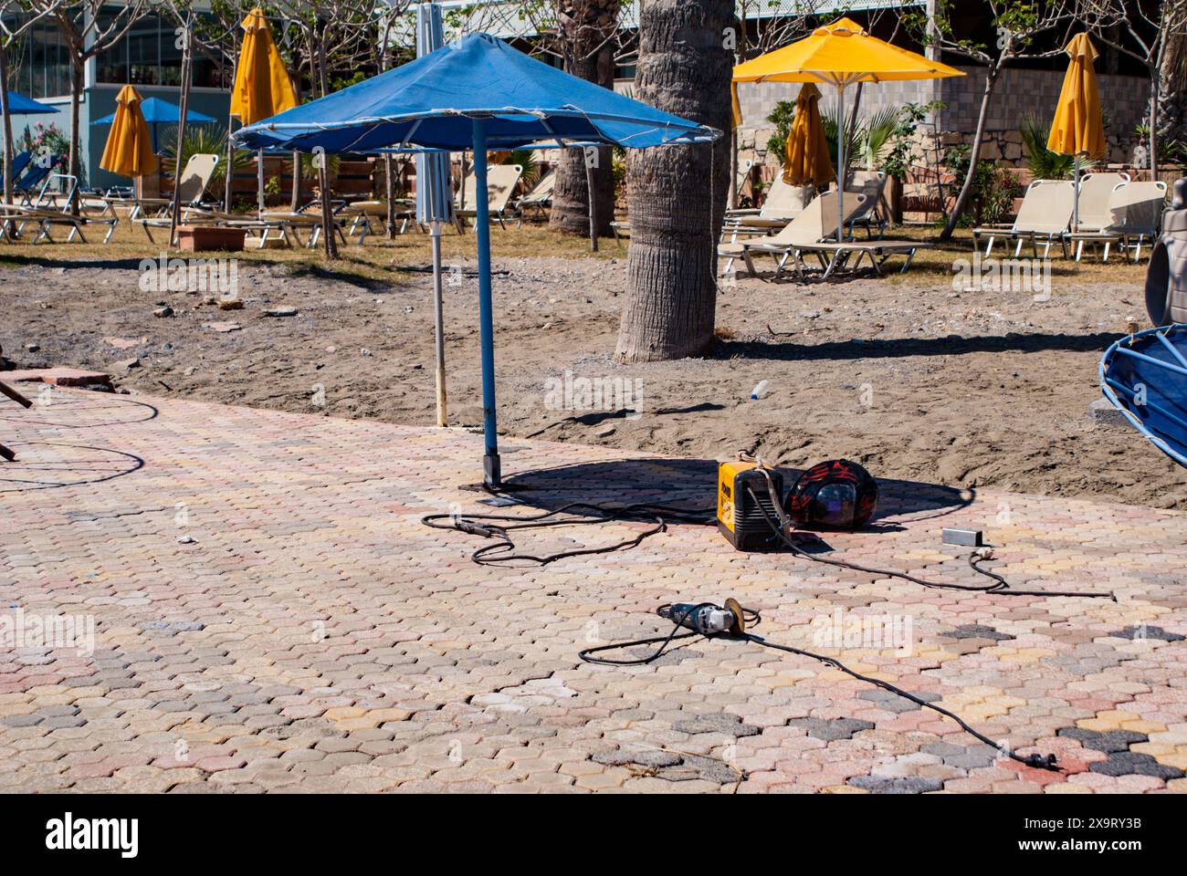 Old sunbeds and beach umbrellas in greek hotel before the start of the ...