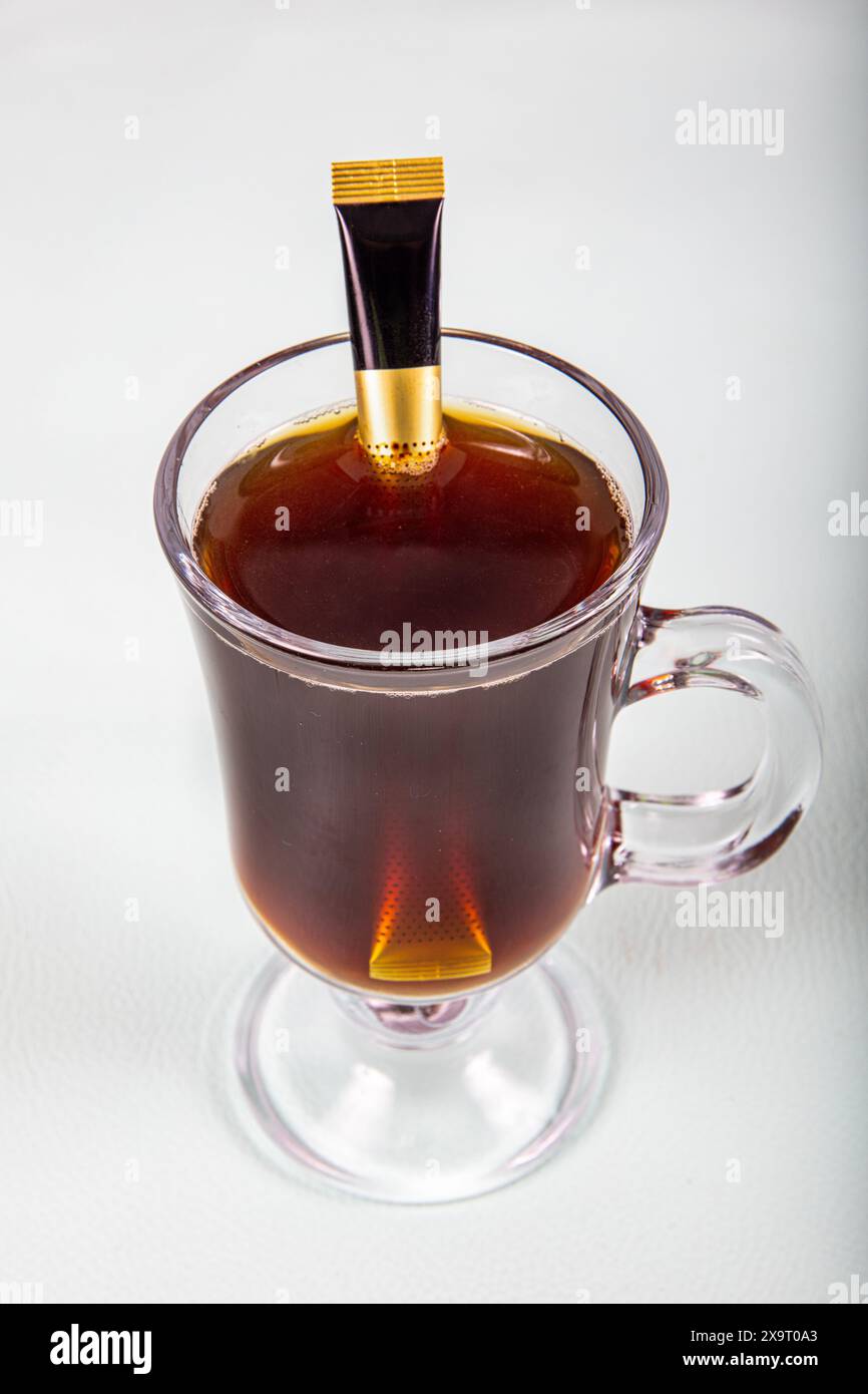 A glass cup of freshly brewed drip coffee. Female hands hold a bag of ...