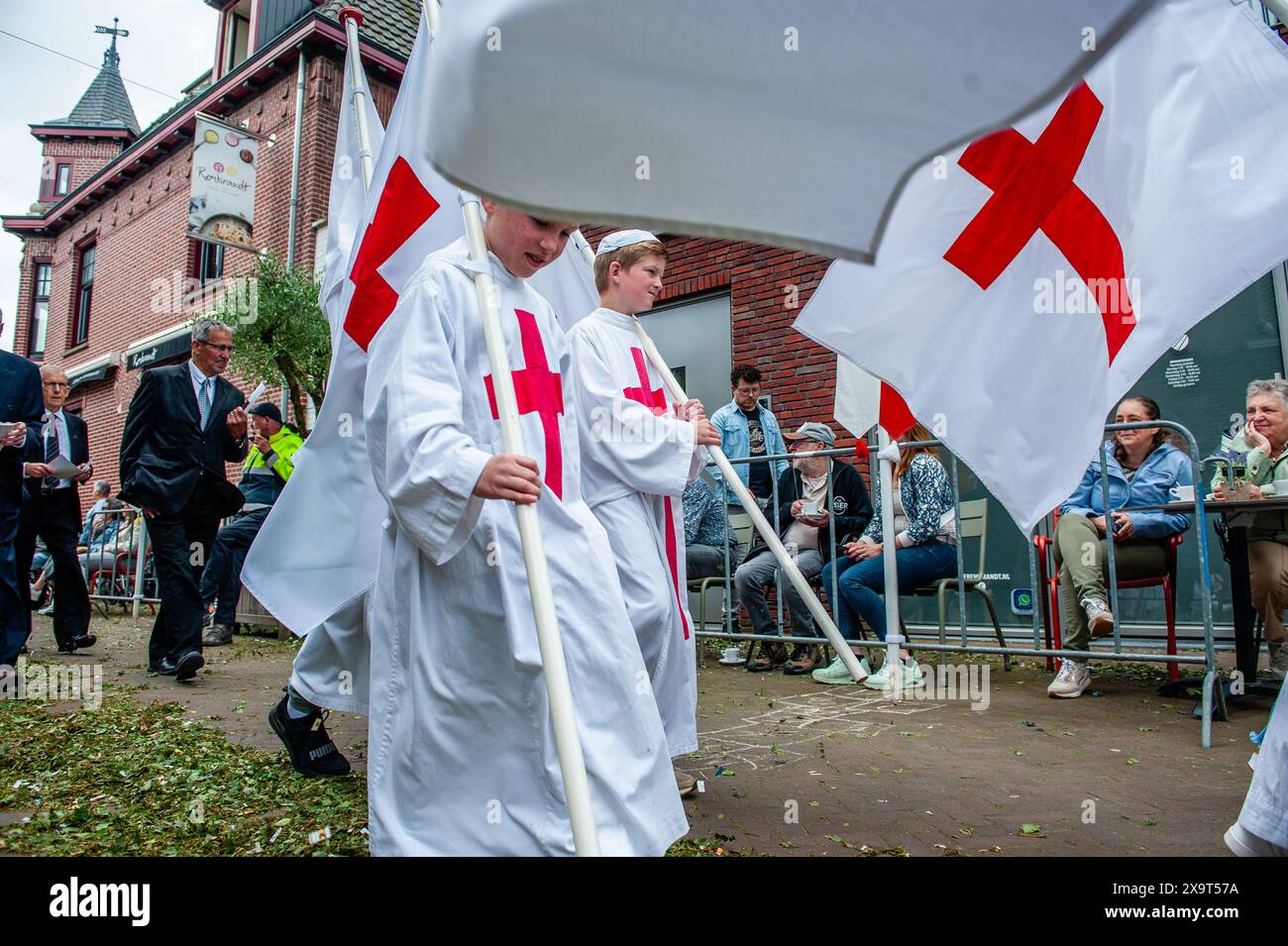 Young boys are seen holding flags with a red cross during the ...