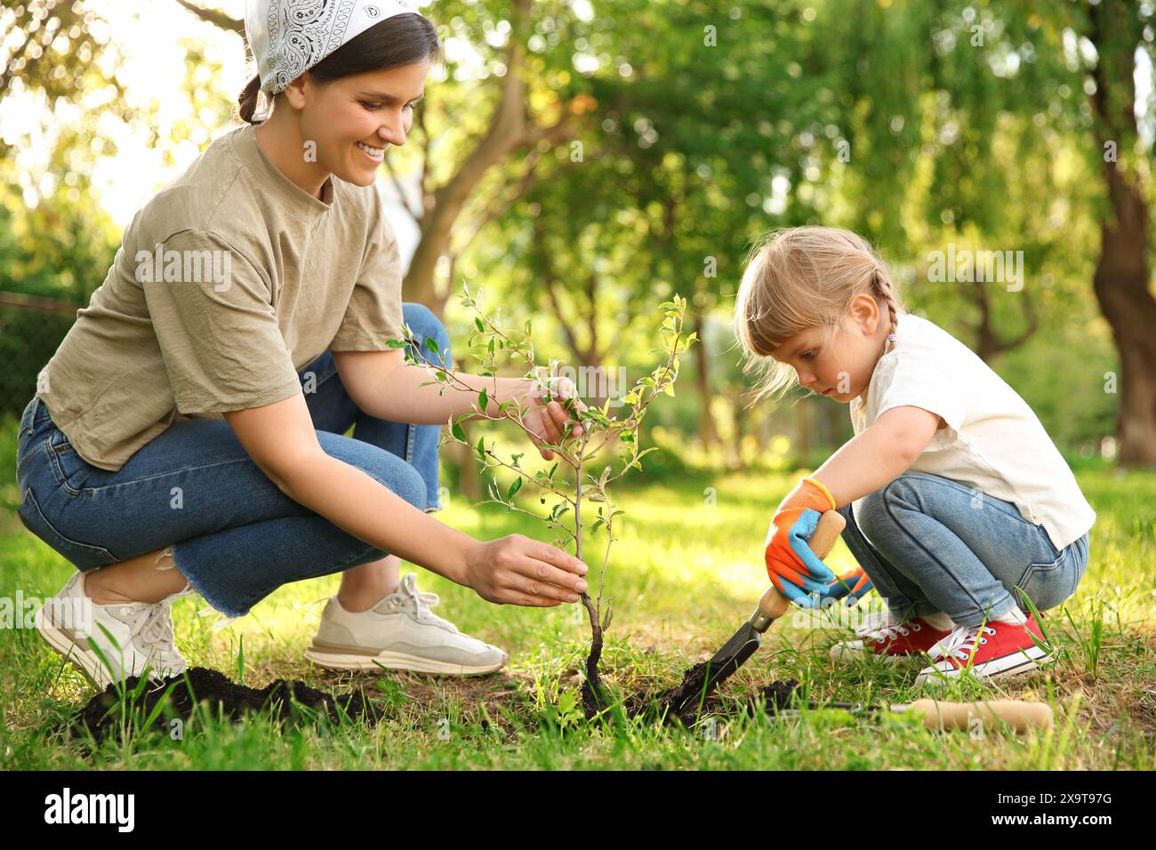 Mother and her daughter planting tree together in garden Stock Photo ...