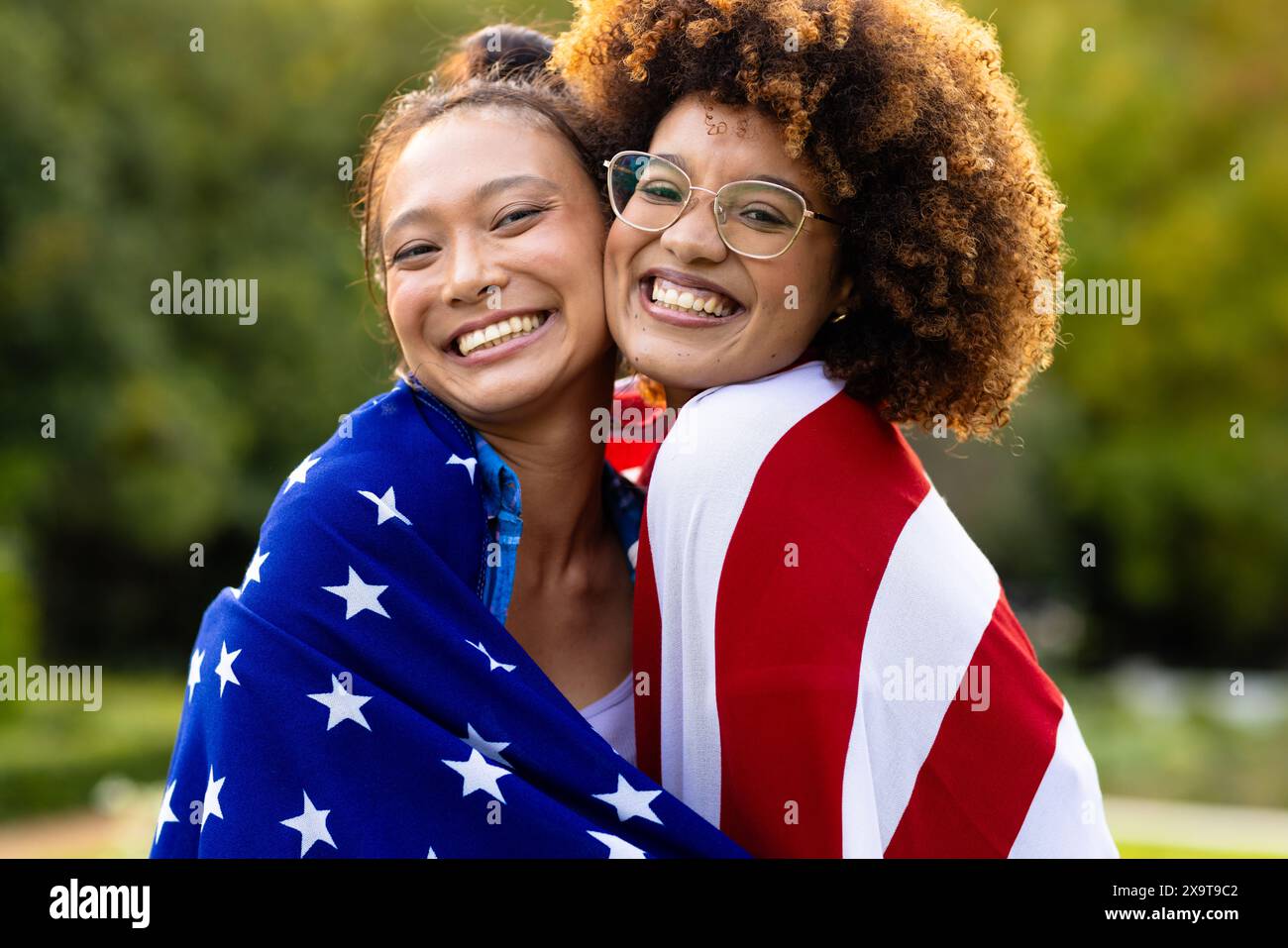 Portrait of happy diverse female friends covered with flag of usa in ...