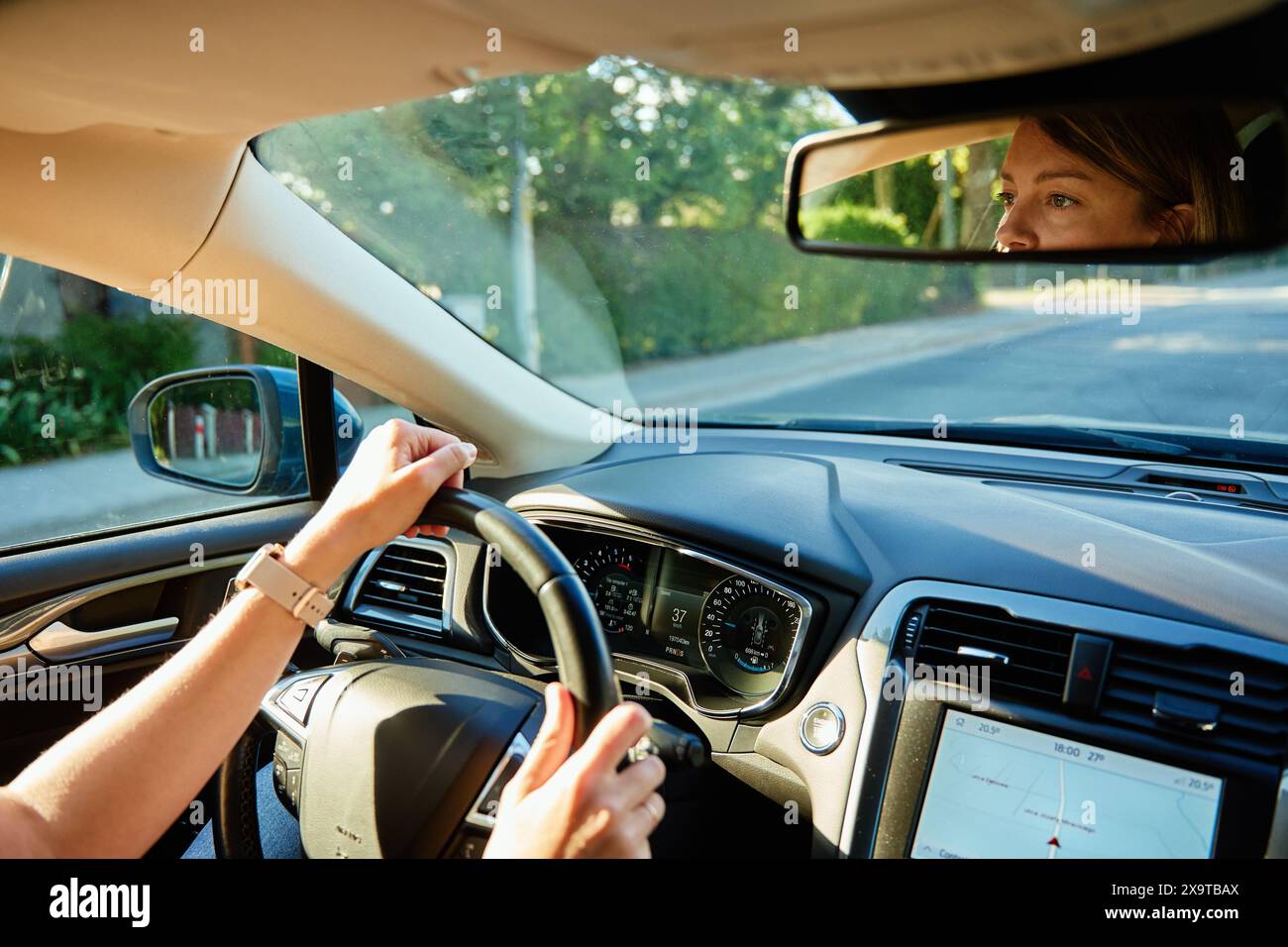 Woman driving car on country road at sunset. Back view of female driver ...