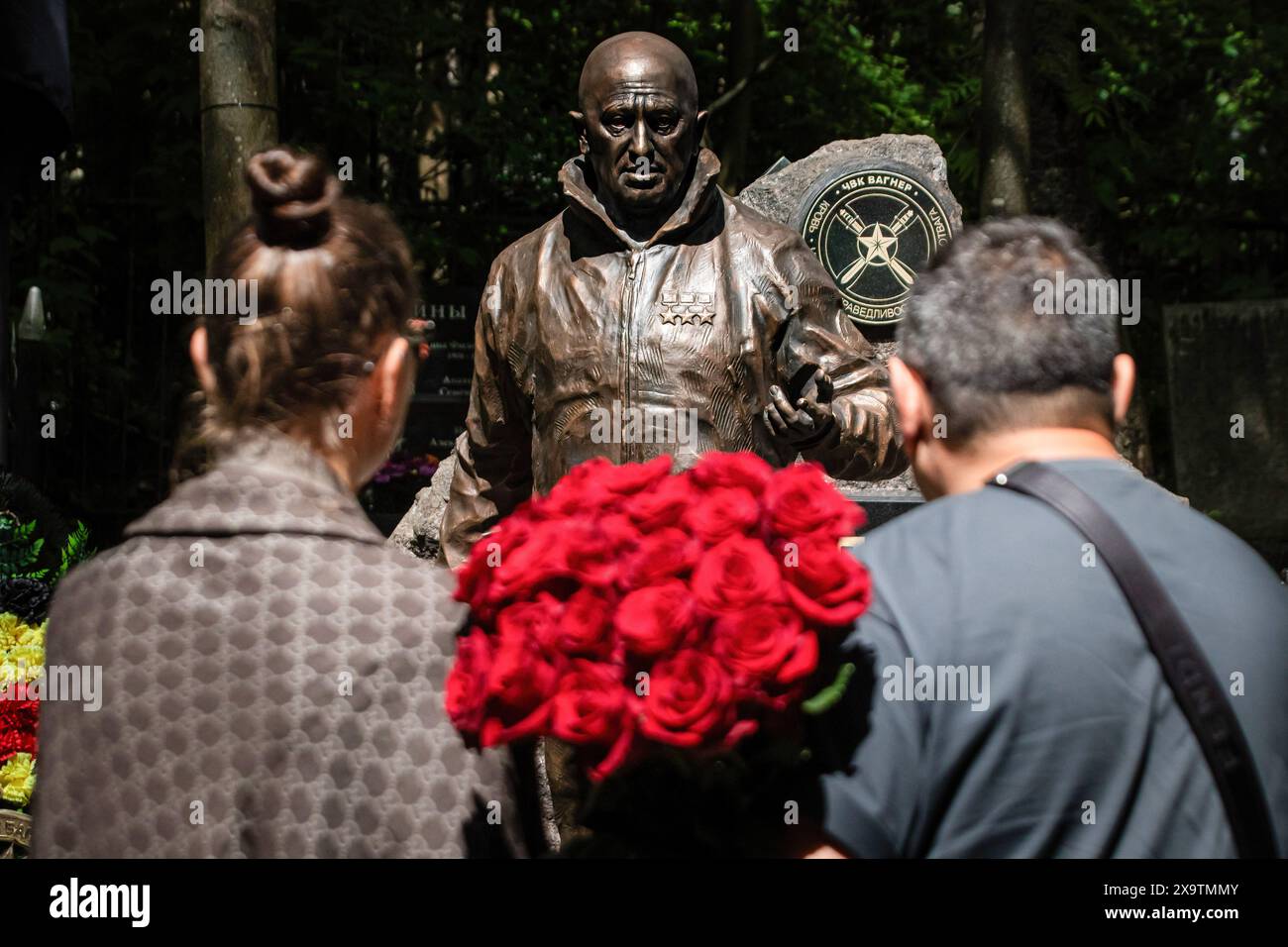 People stand with a bouquet of roses near a sculpture of Russian ...