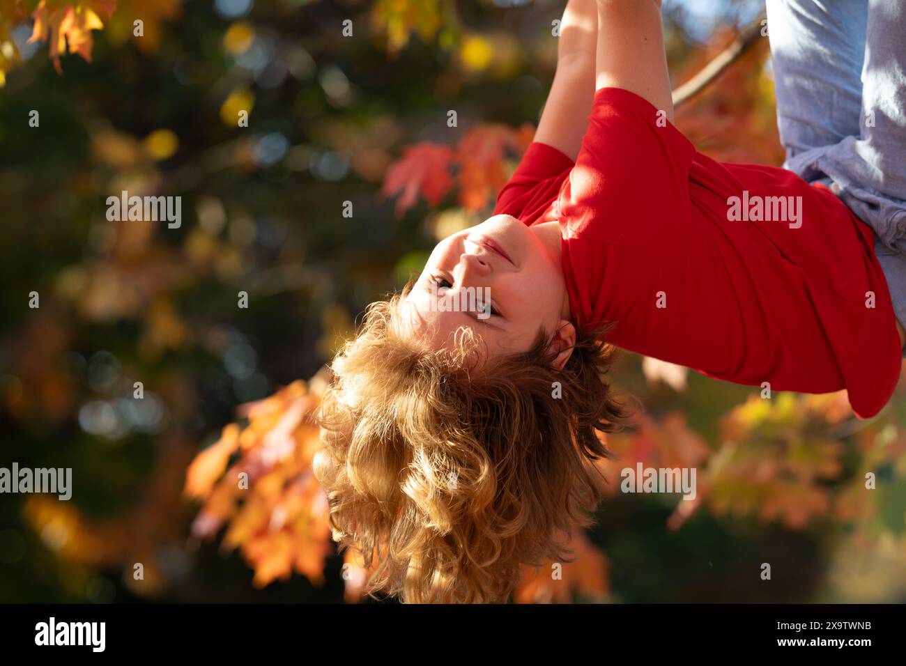 Funny kid climbing a autumn tree in the garden. Active child climbing ...