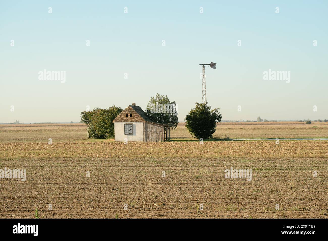 harvested field with farm building, shrubs and anemometer a typical ...