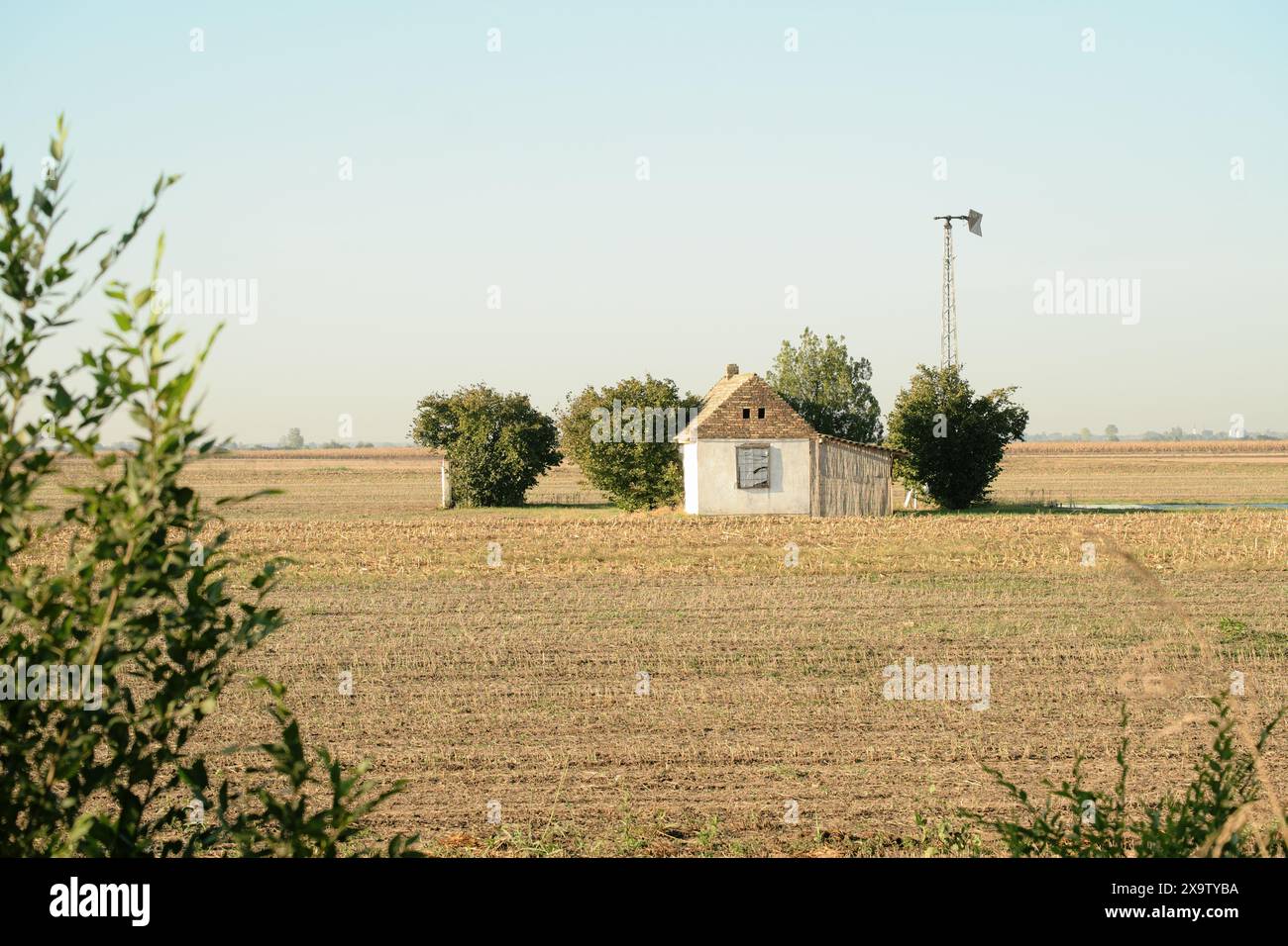 harvested field with farm building, shrubs and anemometer a typical ...