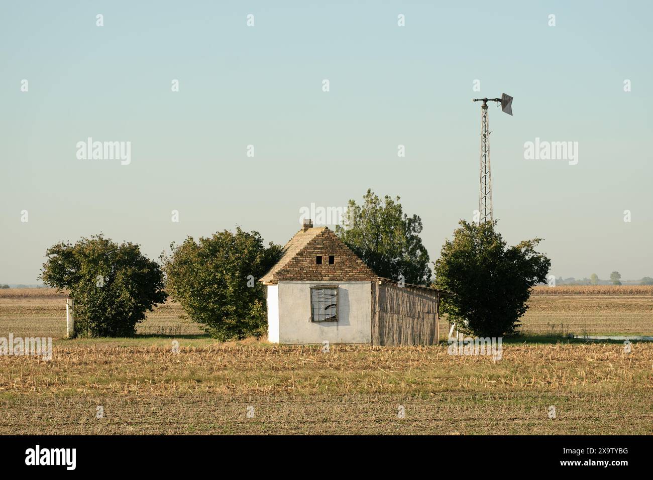 harvested field with farm building, shrubs and anemometer a typical ...