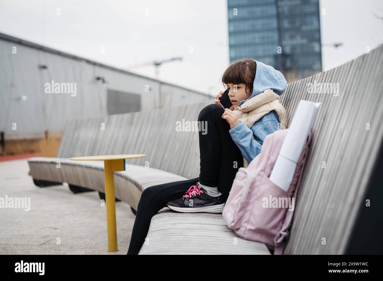 Sad girl phone calling, sitting in front of school building, waiting ...