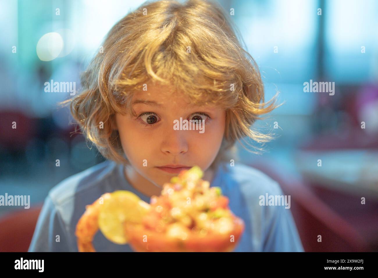 Funny surprised Little boy eating seafood in cafe. Kid eat Food fish ...