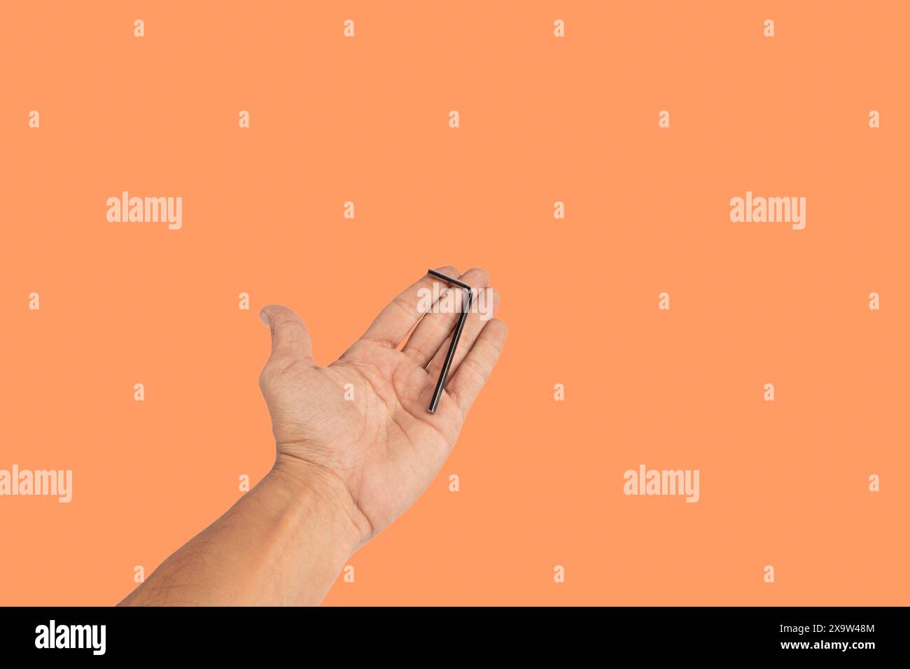 Black male hand offering an allen key isolated on orange background ...