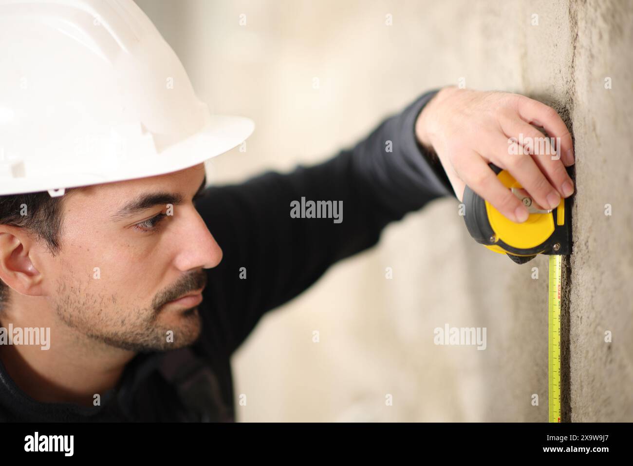 Construction worker using measuring meter on a wall Stock Photo - Alamy