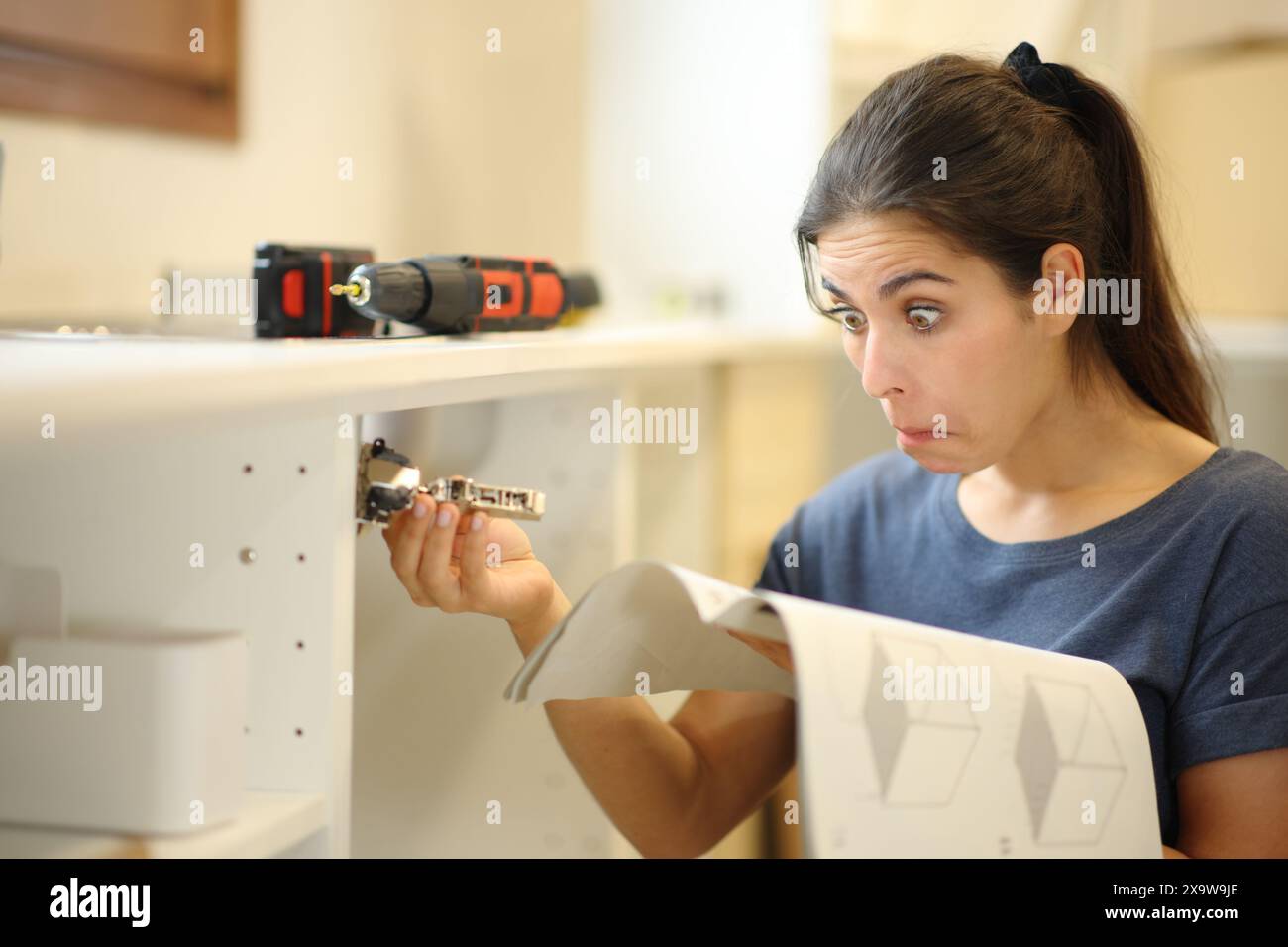 Perplexed woman reading manual assembling furniture in the kitchen ...