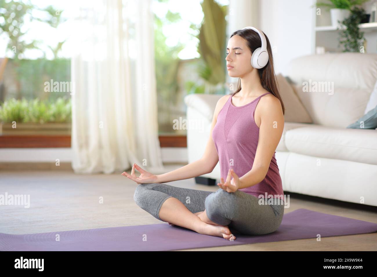 Yogi doing guided yoga exercise wearing headphone at home Stock Photo ...