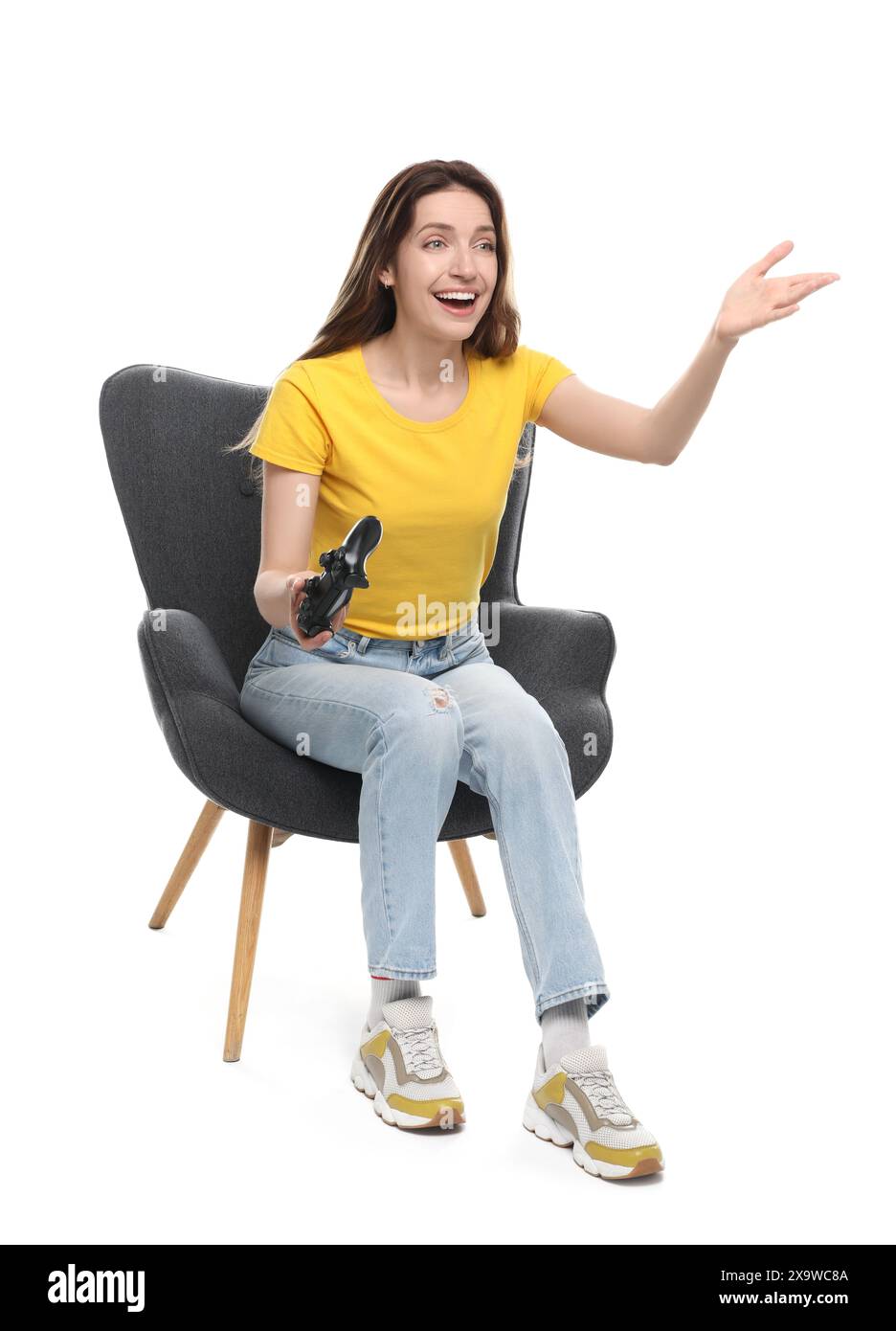 Happy woman with game controller sitting in armchair on white ...