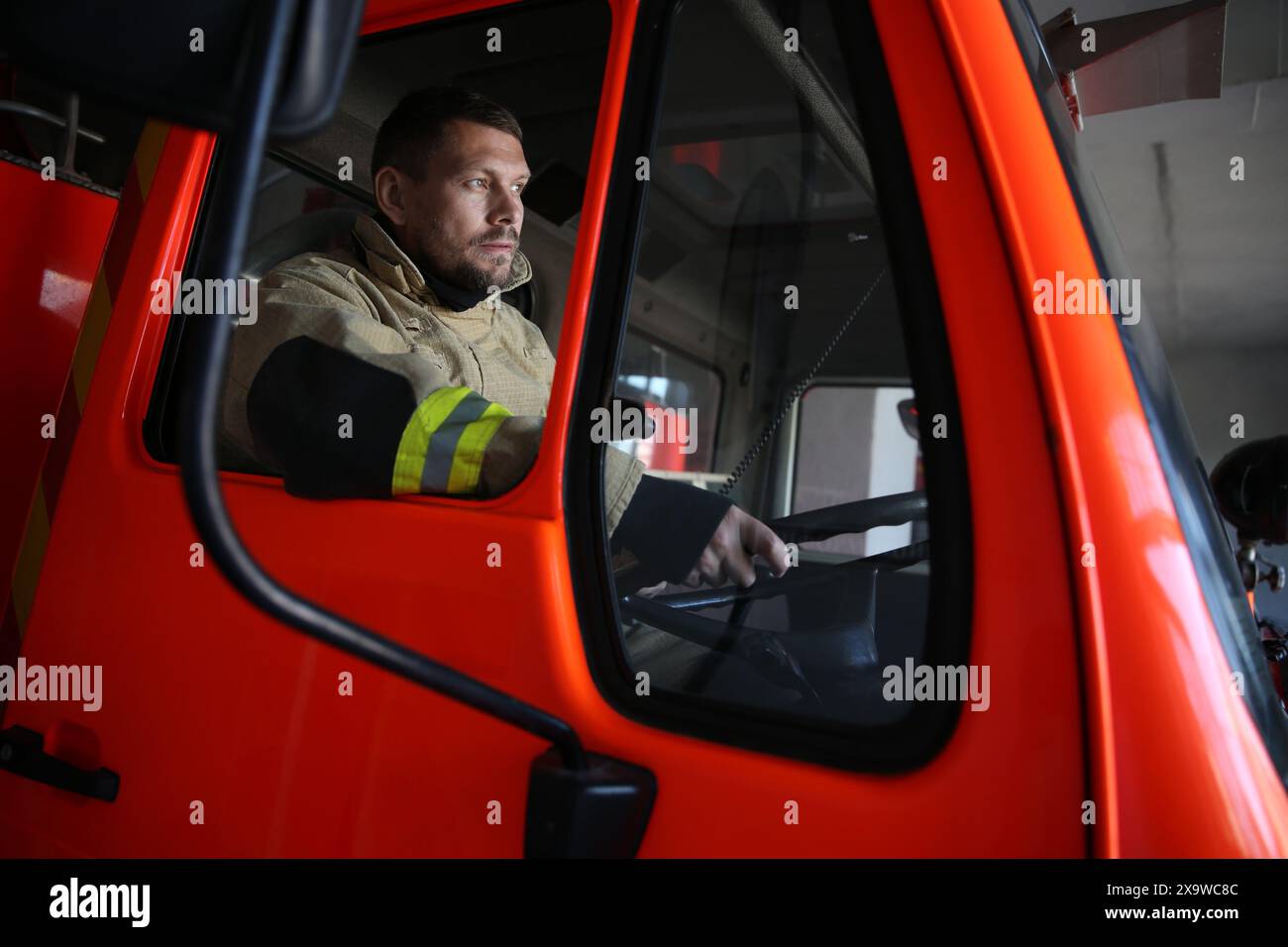Firefighter in uniform driving modern fire truck Stock Photo - Alamy