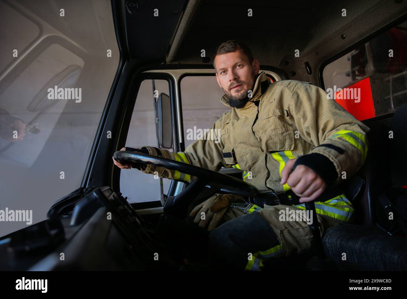 Firefighter in uniform driving modern fire truck Stock Photo - Alamy