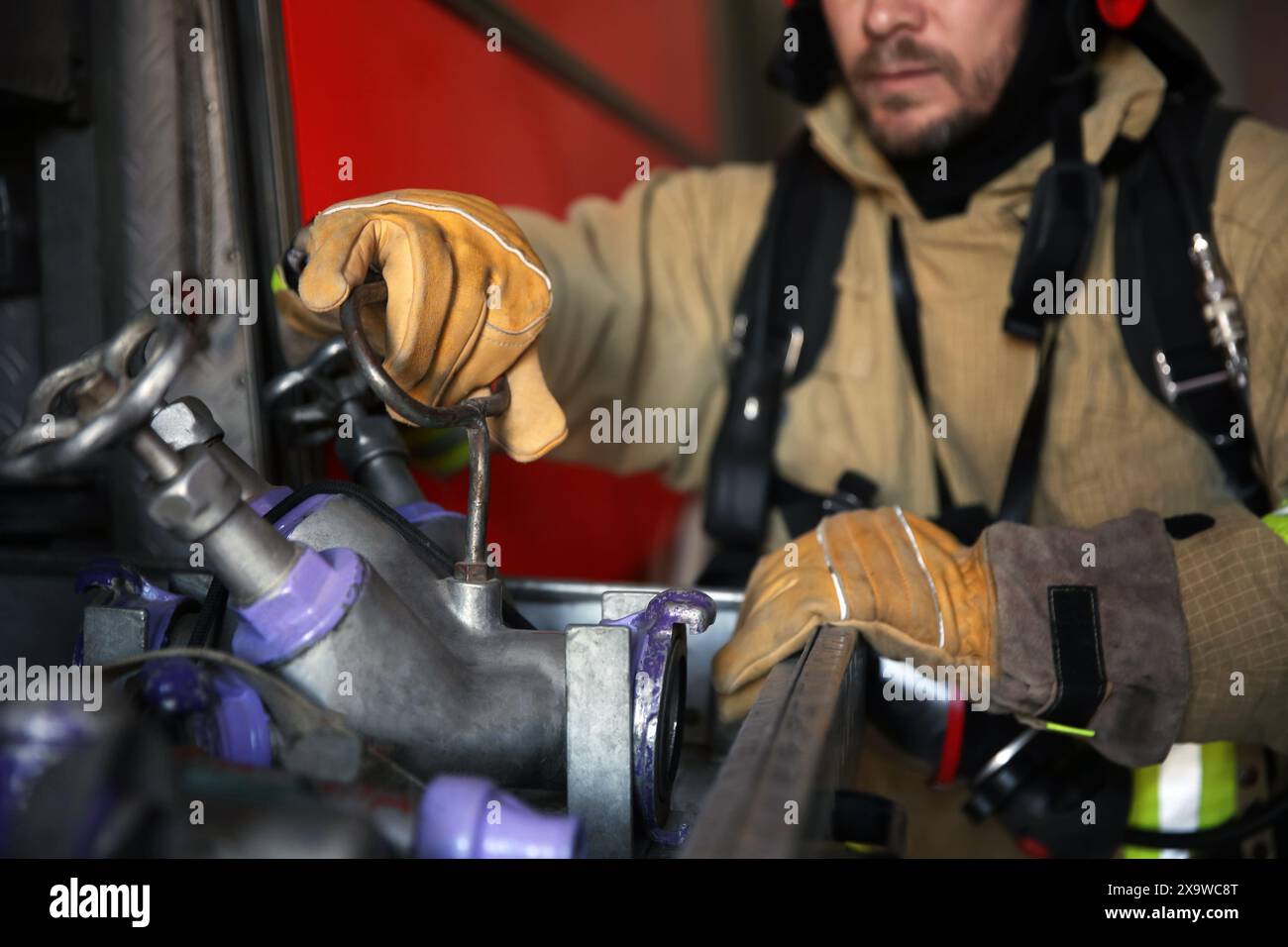 Firefighter in uniform with fire engine equipment at station, selective ...