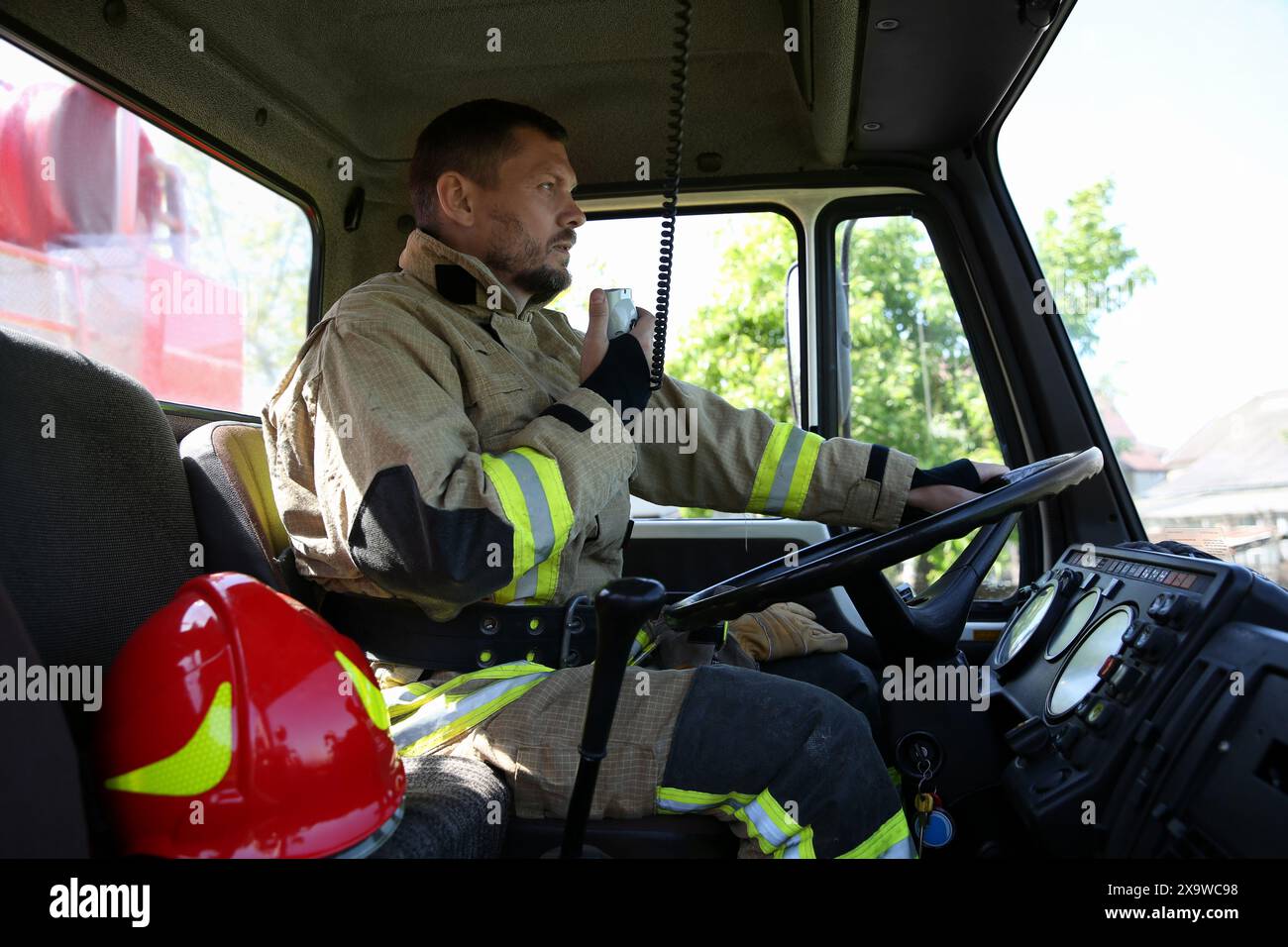 Firefighter using portable radio set while driving fire truck Stock ...