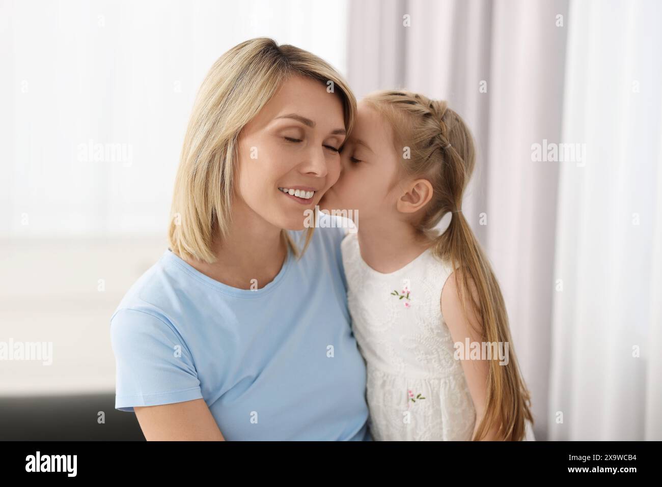 Daughter kissing her happy mother at home Stock Photo - Alamy