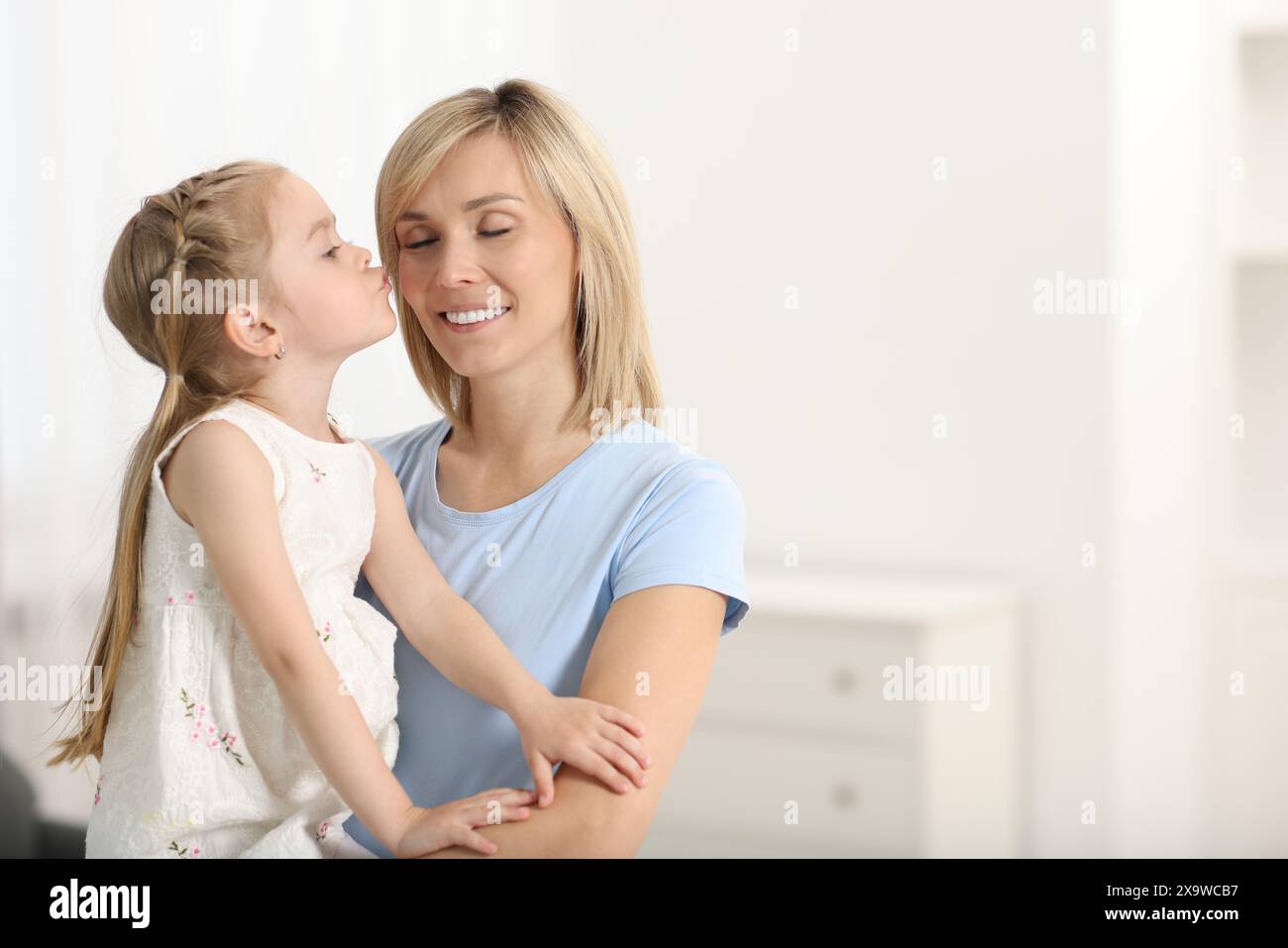 Daughter kissing her happy mother at home. Space for text Stock Photo ...