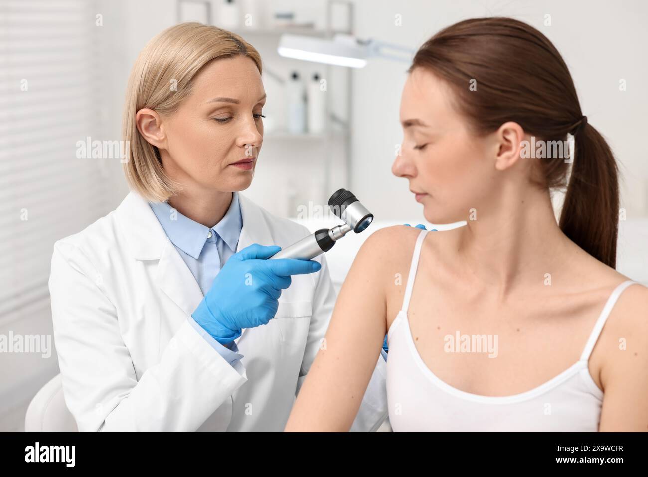Dermatologist with dermatoscope examining patient in clinic Stock Photo ...