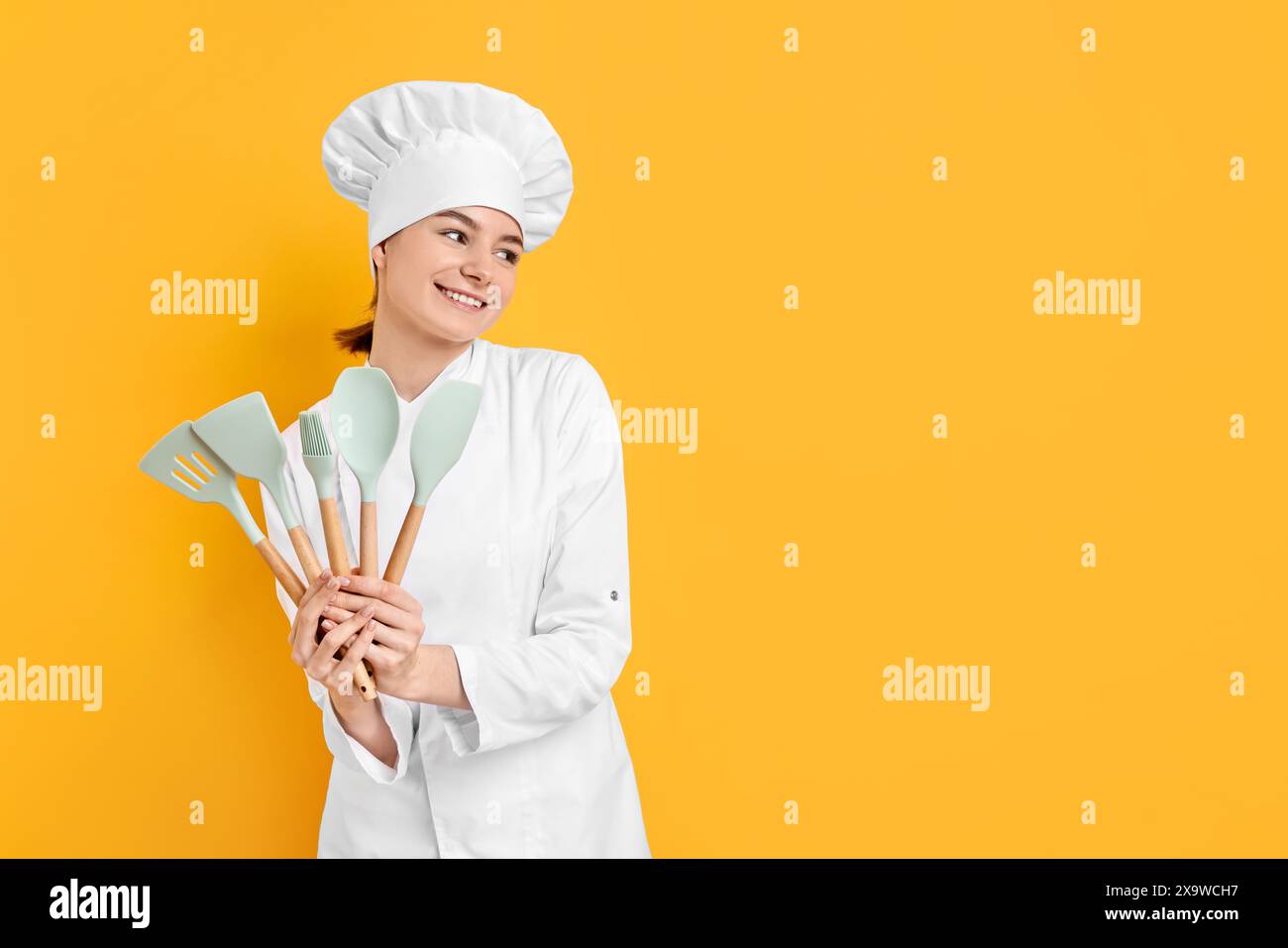 Professional chef with kitchen utensils on yellow background. Space for ...