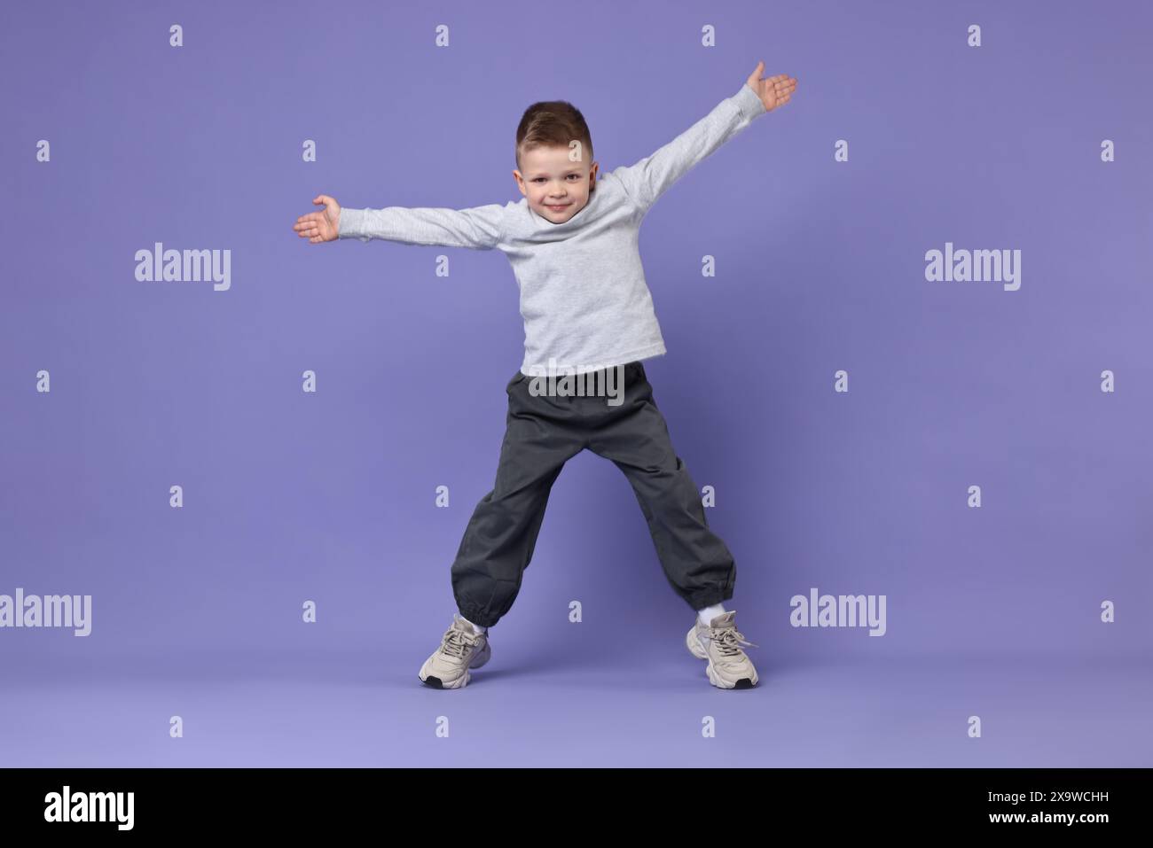 Happy little boy dancing on violet background Stock Photo - Alamy