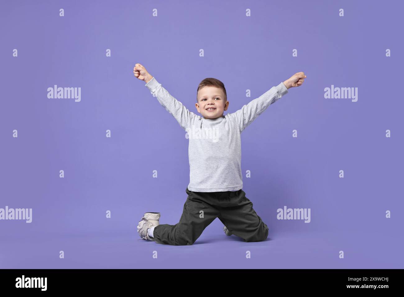 Happy little boy dancing on violet background Stock Photo - Alamy
