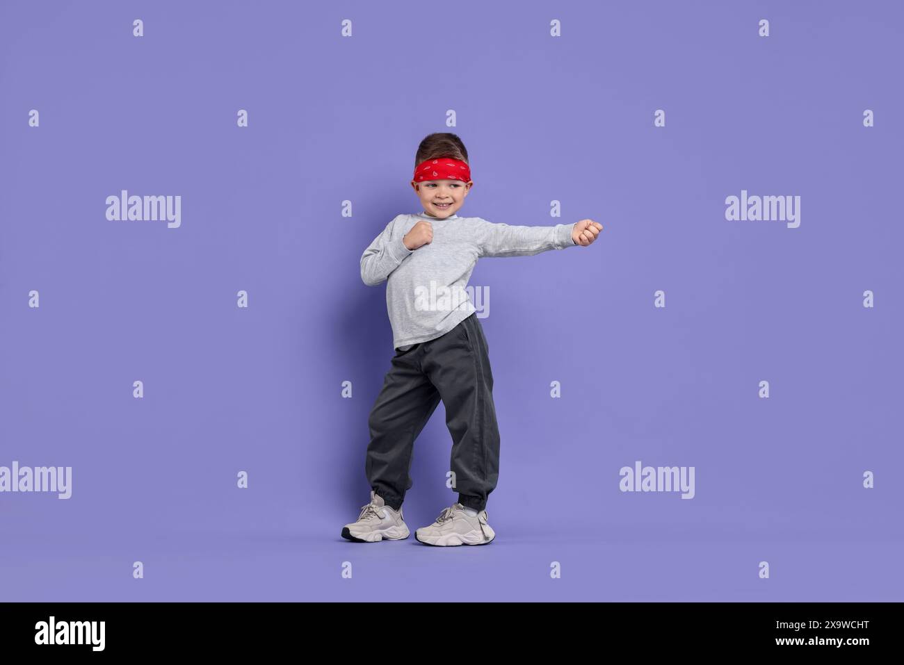 Happy little boy dancing on violet background Stock Photo - Alamy