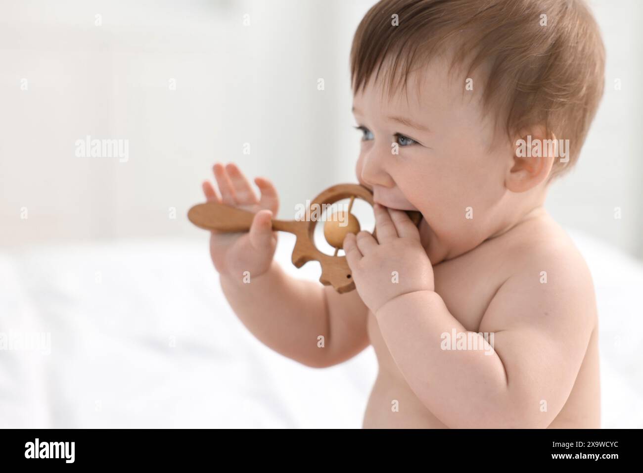 Cute baby boy with wooden rattle at home Stock Photo - Alamy