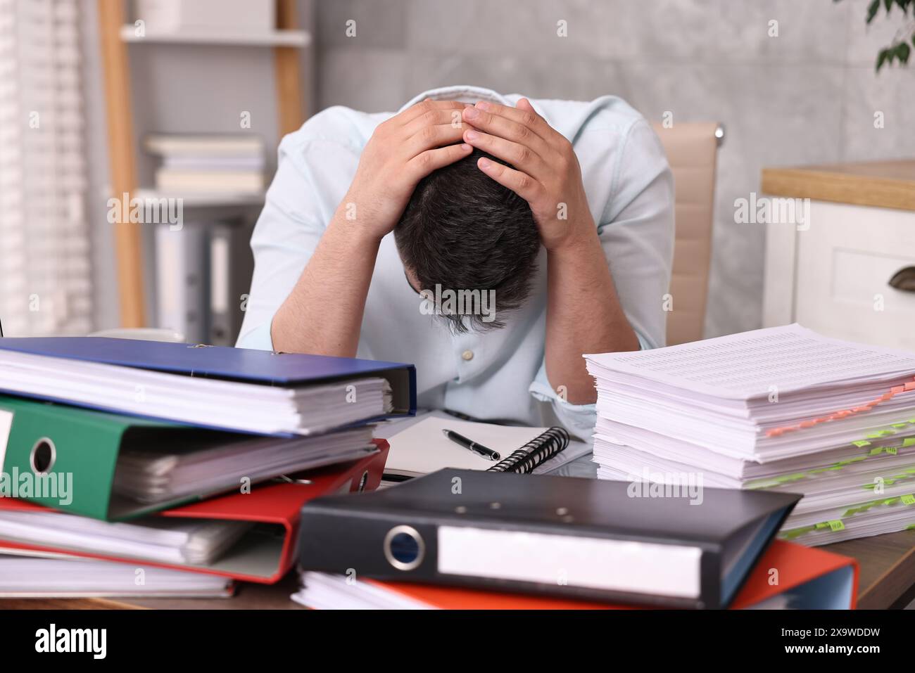 Overwhelmed man surrounded by documents at workplace in office Stock ...
