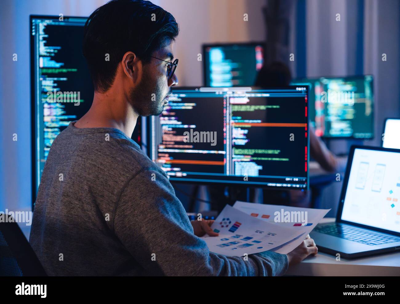Asian Software Developers Working On Multiple Screens Displaying Code And Application Diagrams