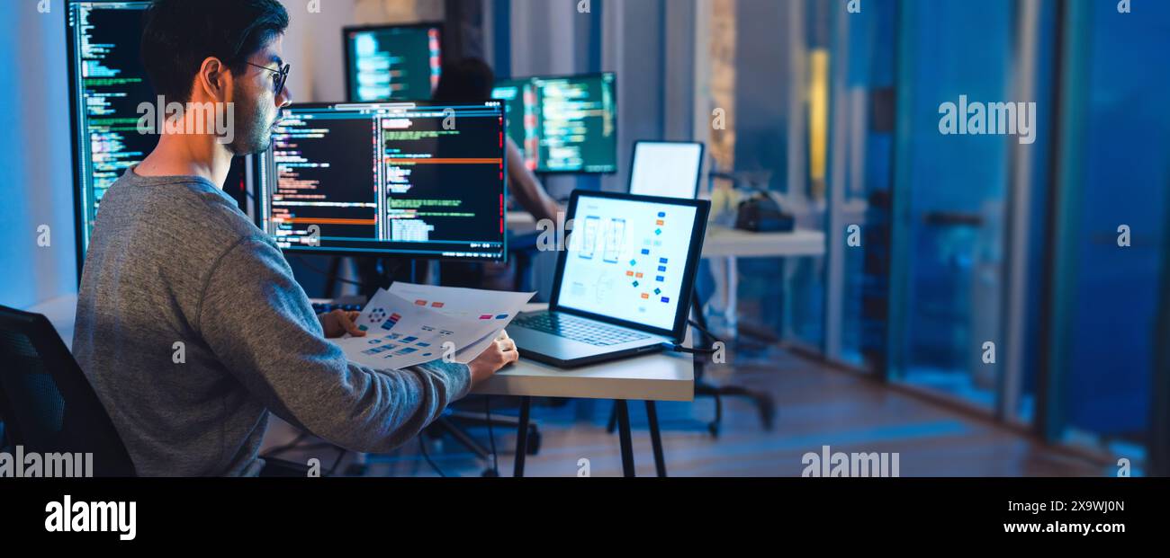 Asian software developers working on multiple screens displaying code and application diagrams ...